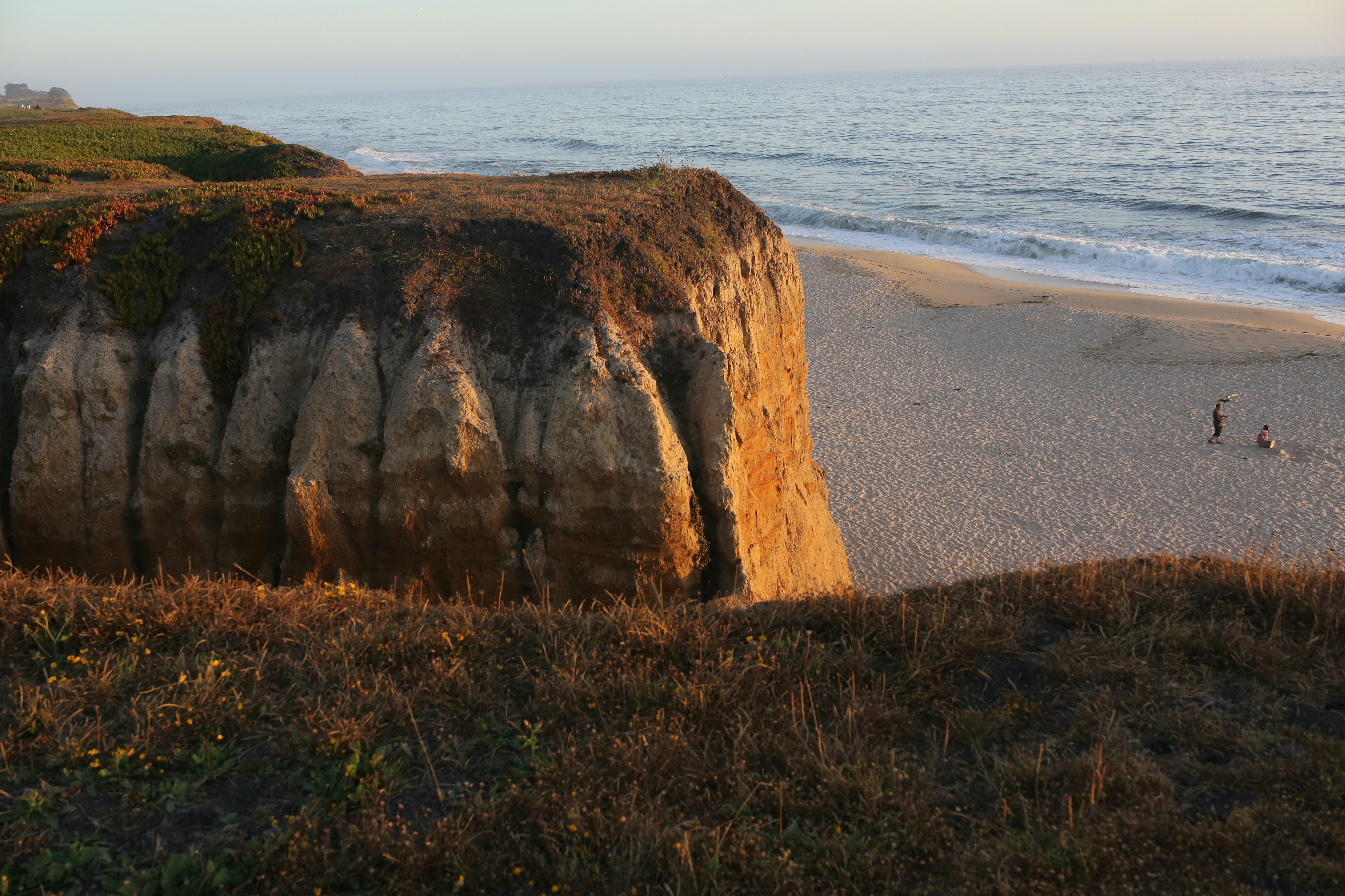 A cliff on a beach with a body of water in the background photo – Free ...