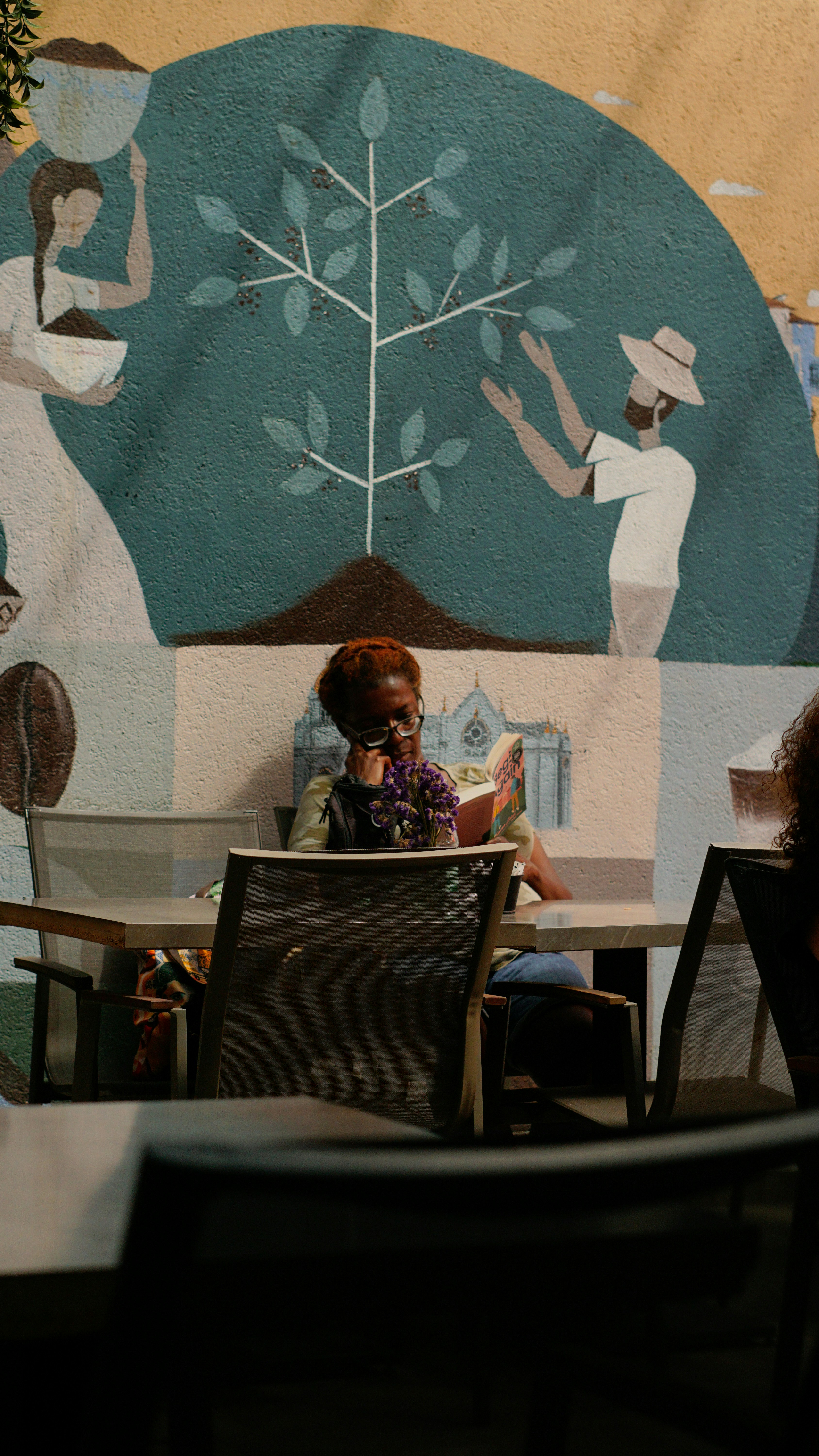 Reading Under a Wall Mural: A Quiet Moment at the Café