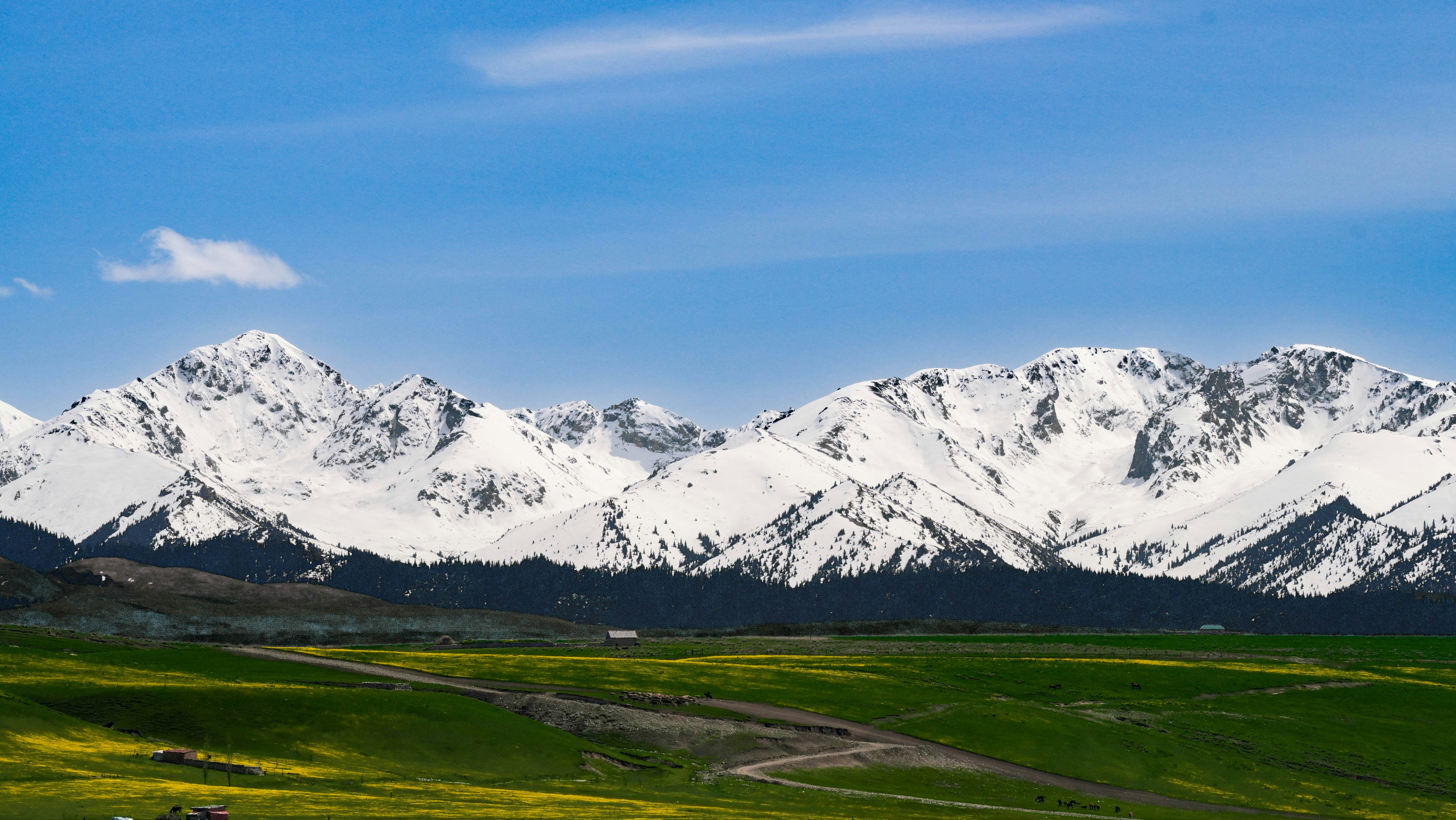 A large mountain range in the distance with a green field in the ...