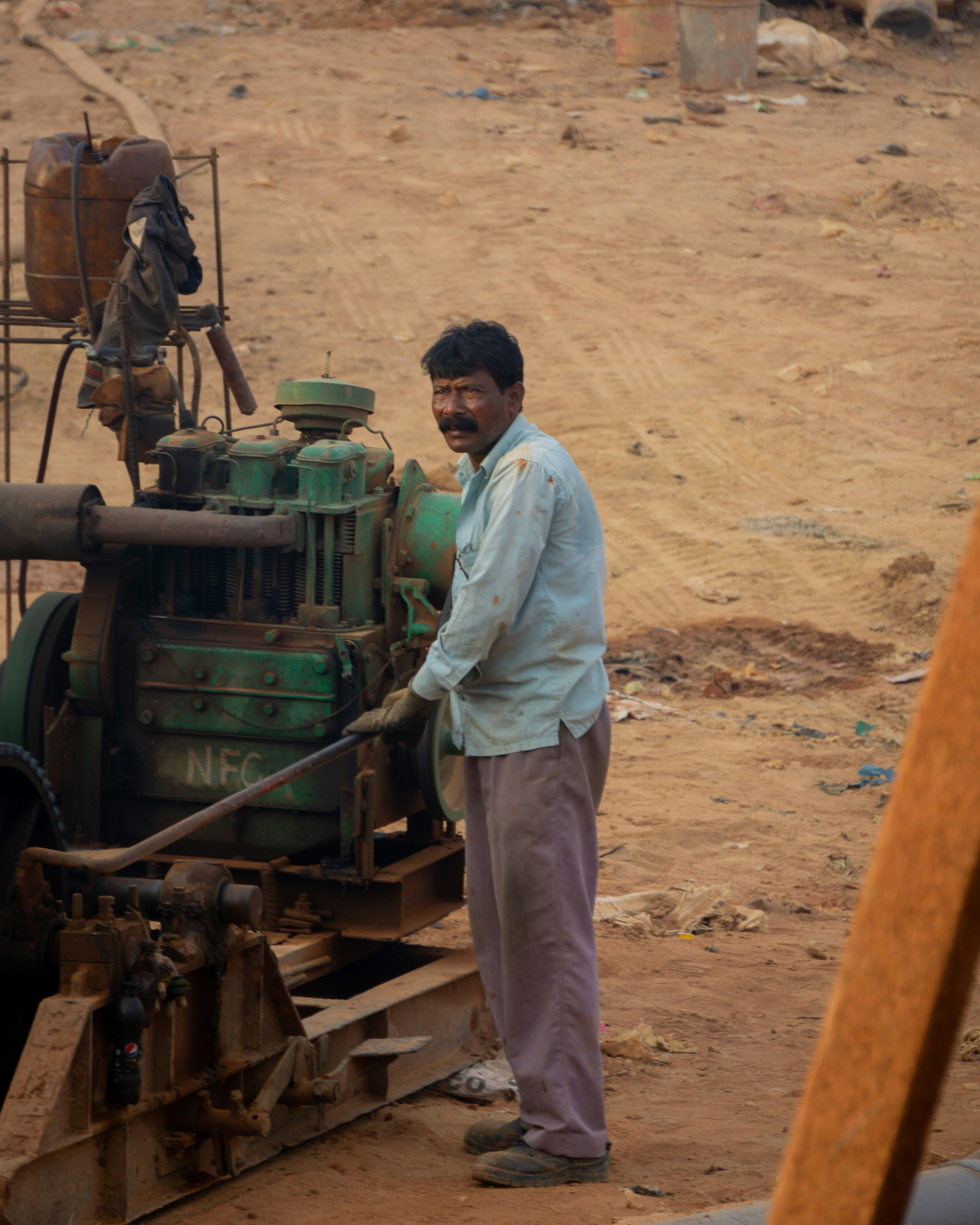 A man standing next to a machine in the dirt photo – Free Teamwork ...