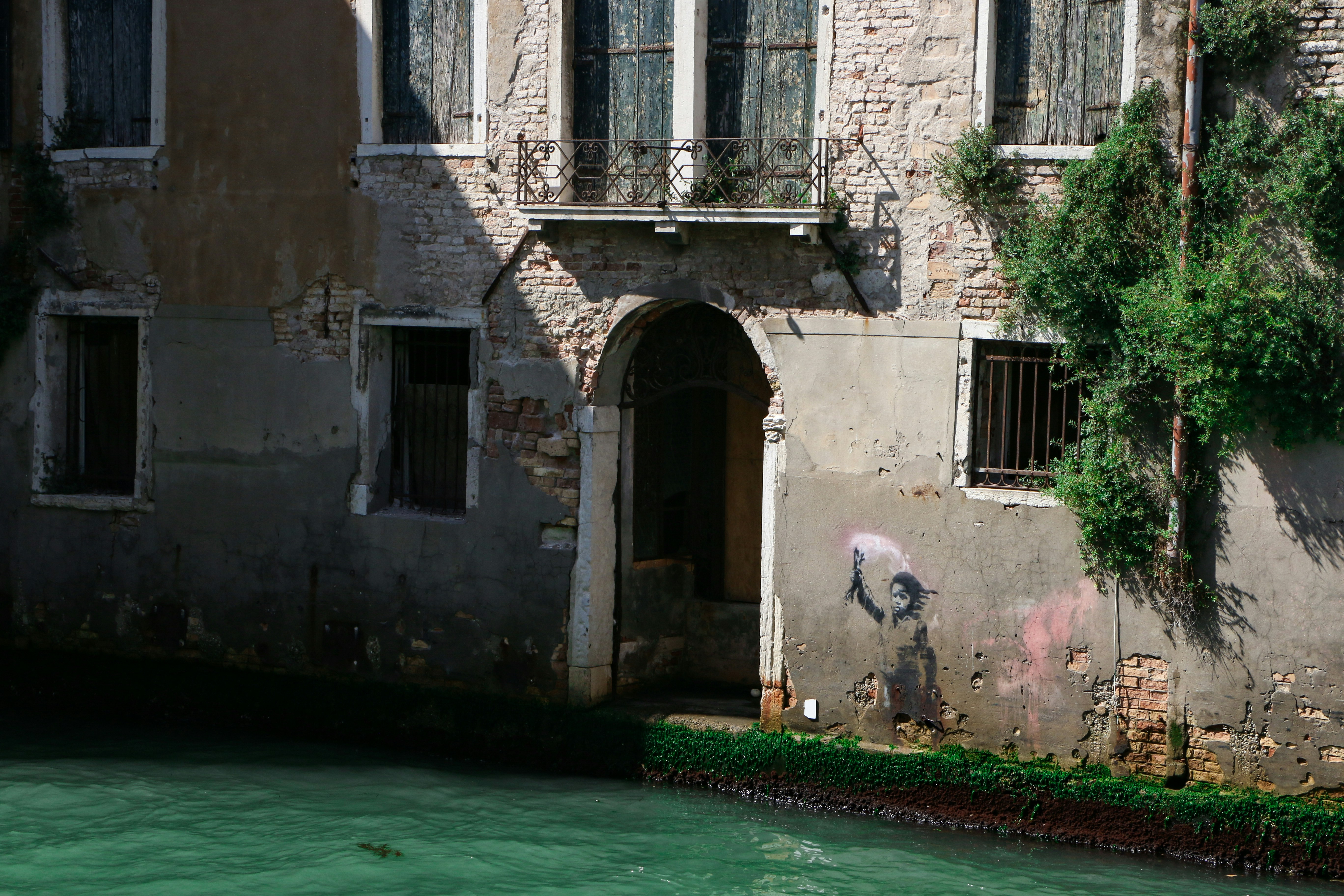 Archway Over Green Water: Weathered Facade in a Venetian Canal