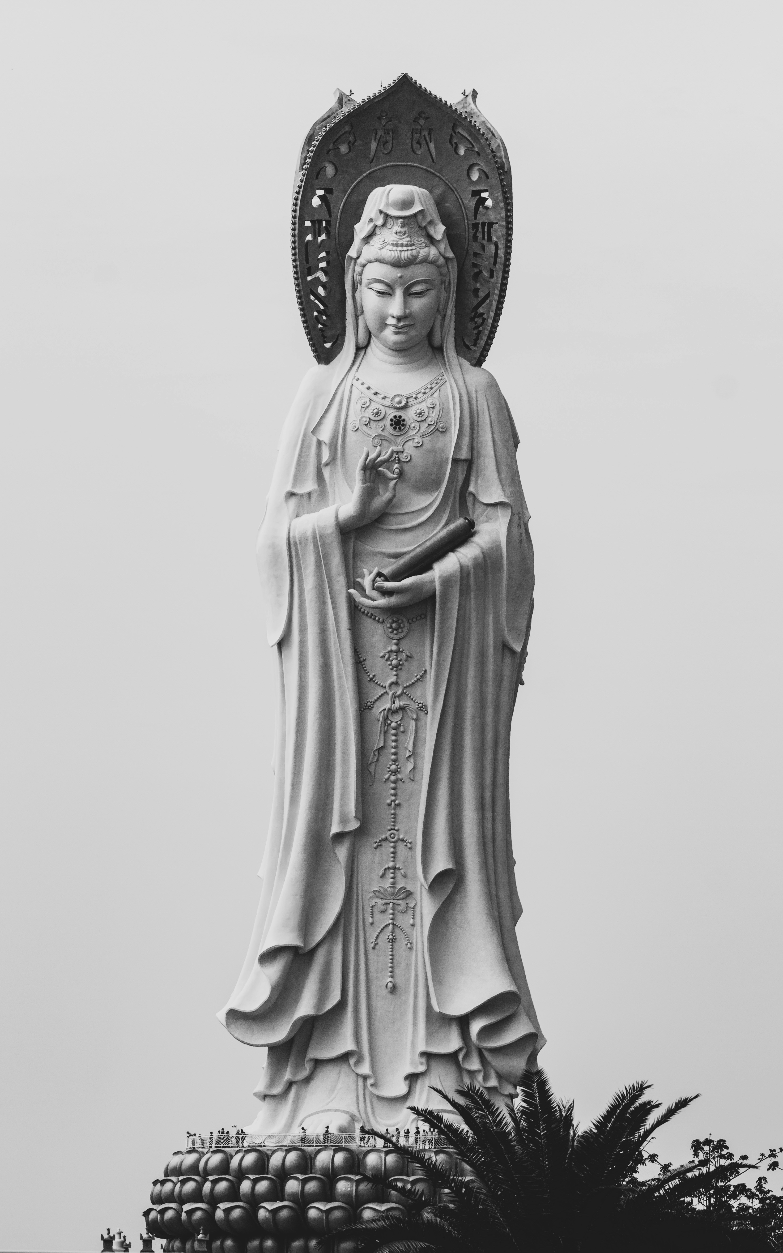 A large white buddha statue sitting on top of a lush green field