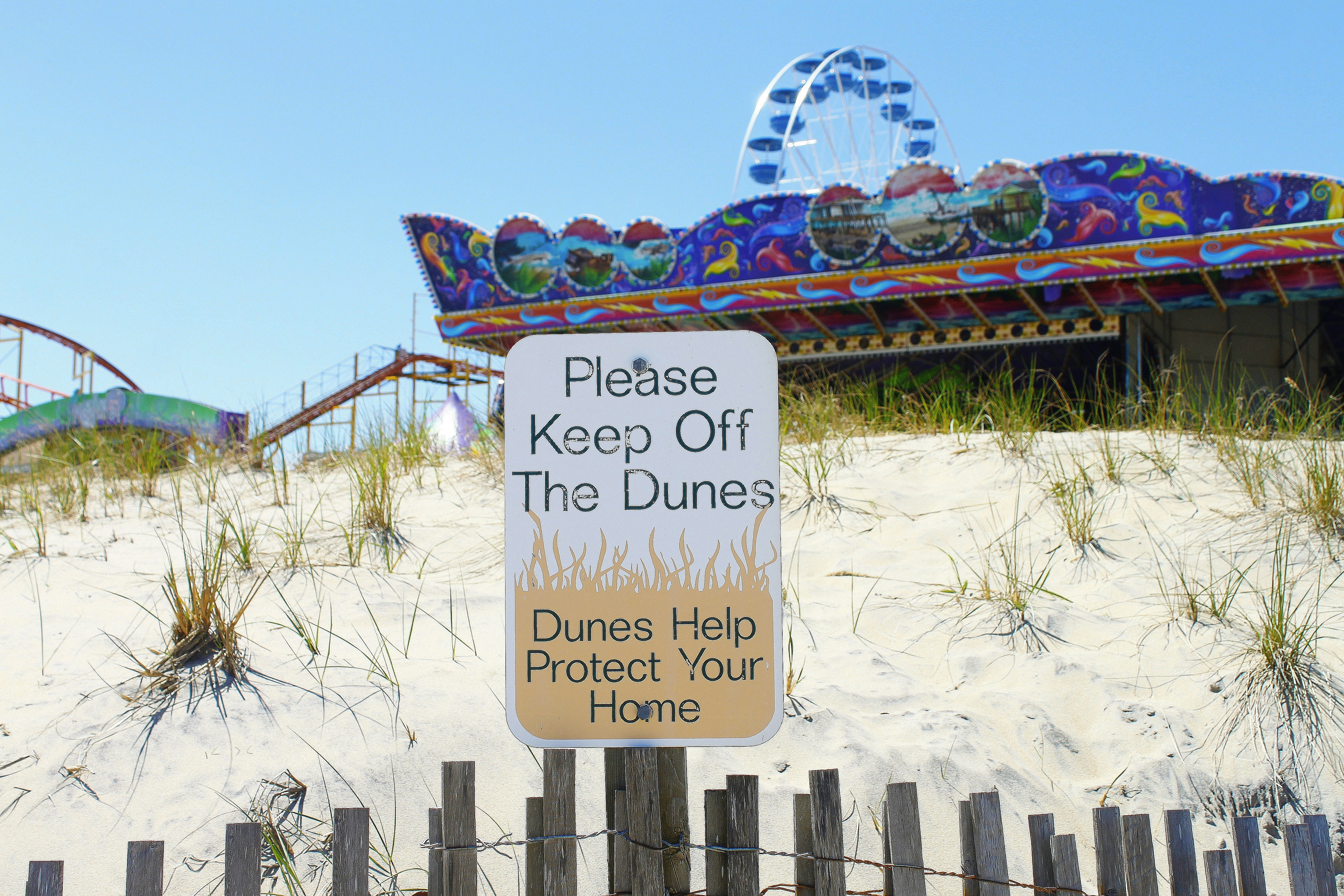 A sign on a fence that says please keep off the dunes photo – Free Ocean city Image on Unsplash