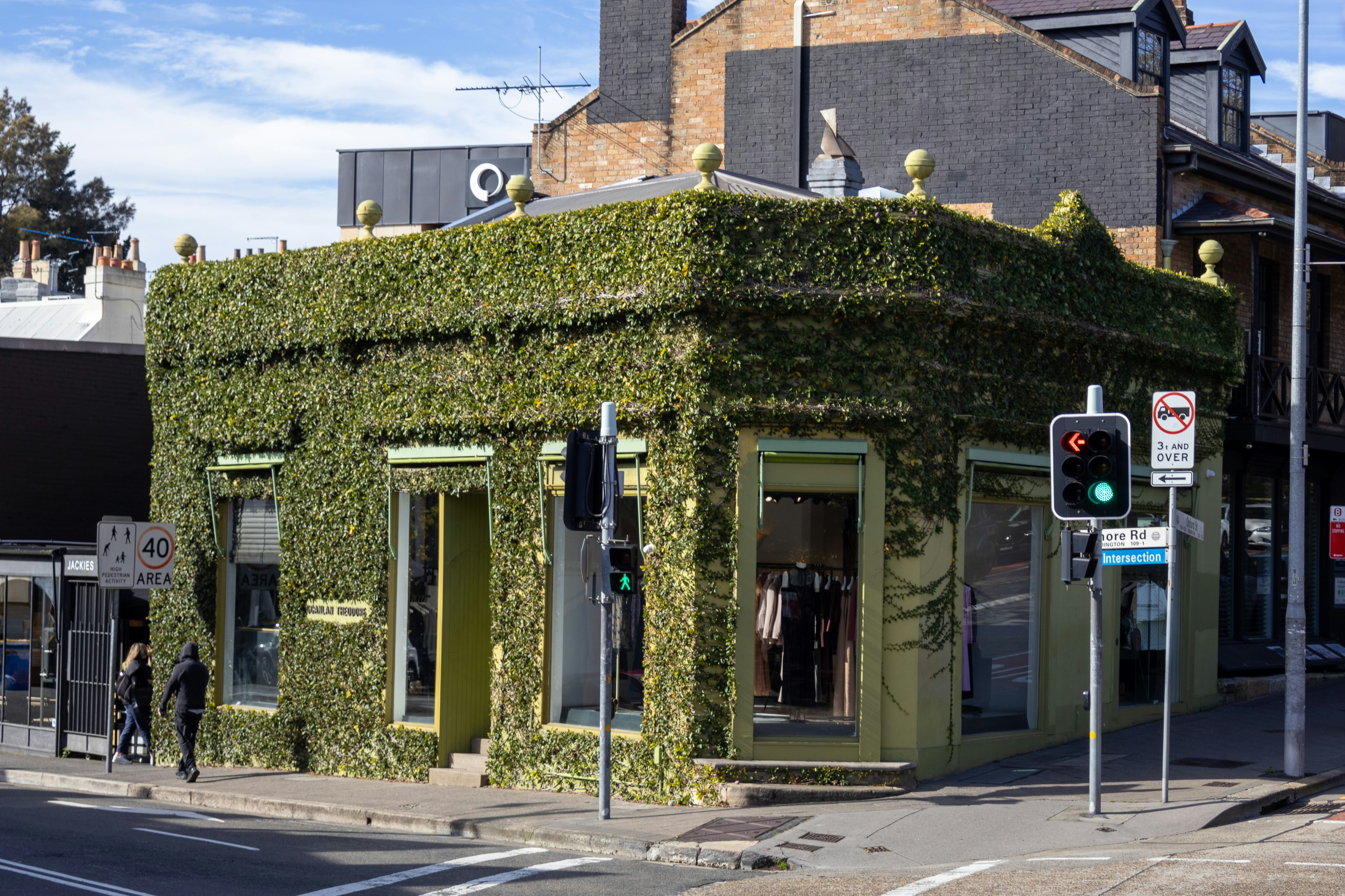 A building covered in vines on the corner of a streetDohyuk You