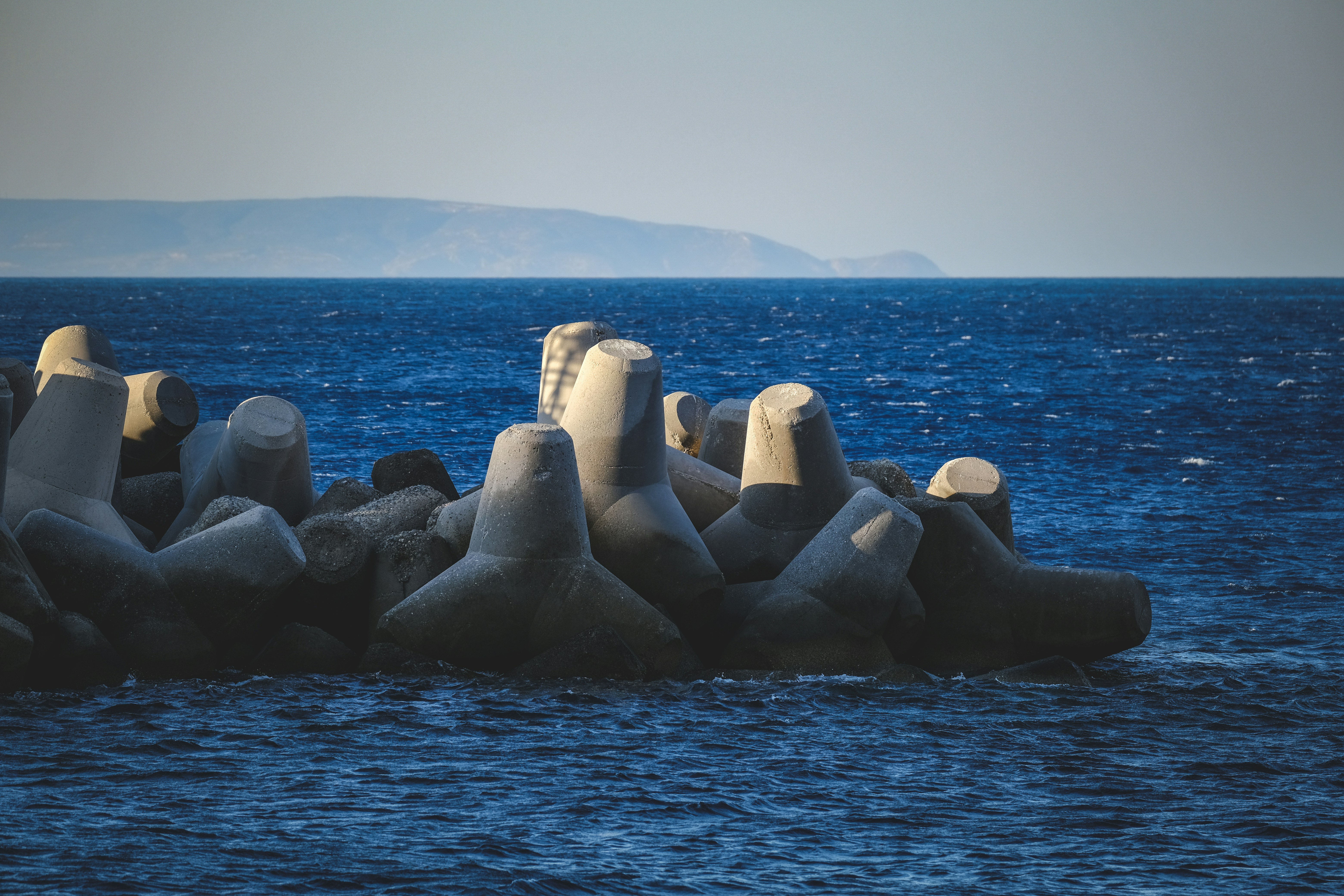 Concrete Guardians on the Blue: Tetrapod Breakwater Against a Calm Sea