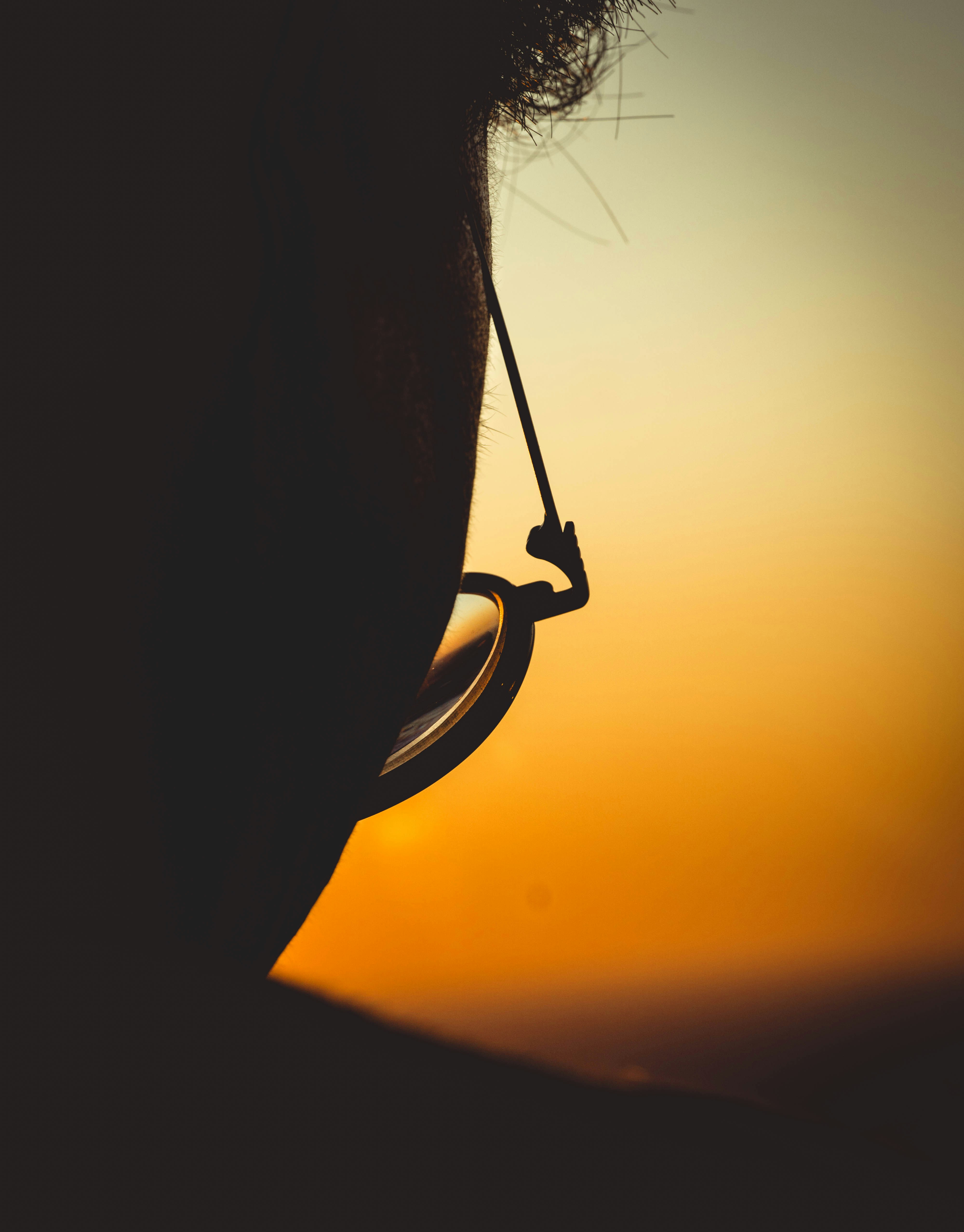A silhouette of a person wearing glasses with a sunset in the background