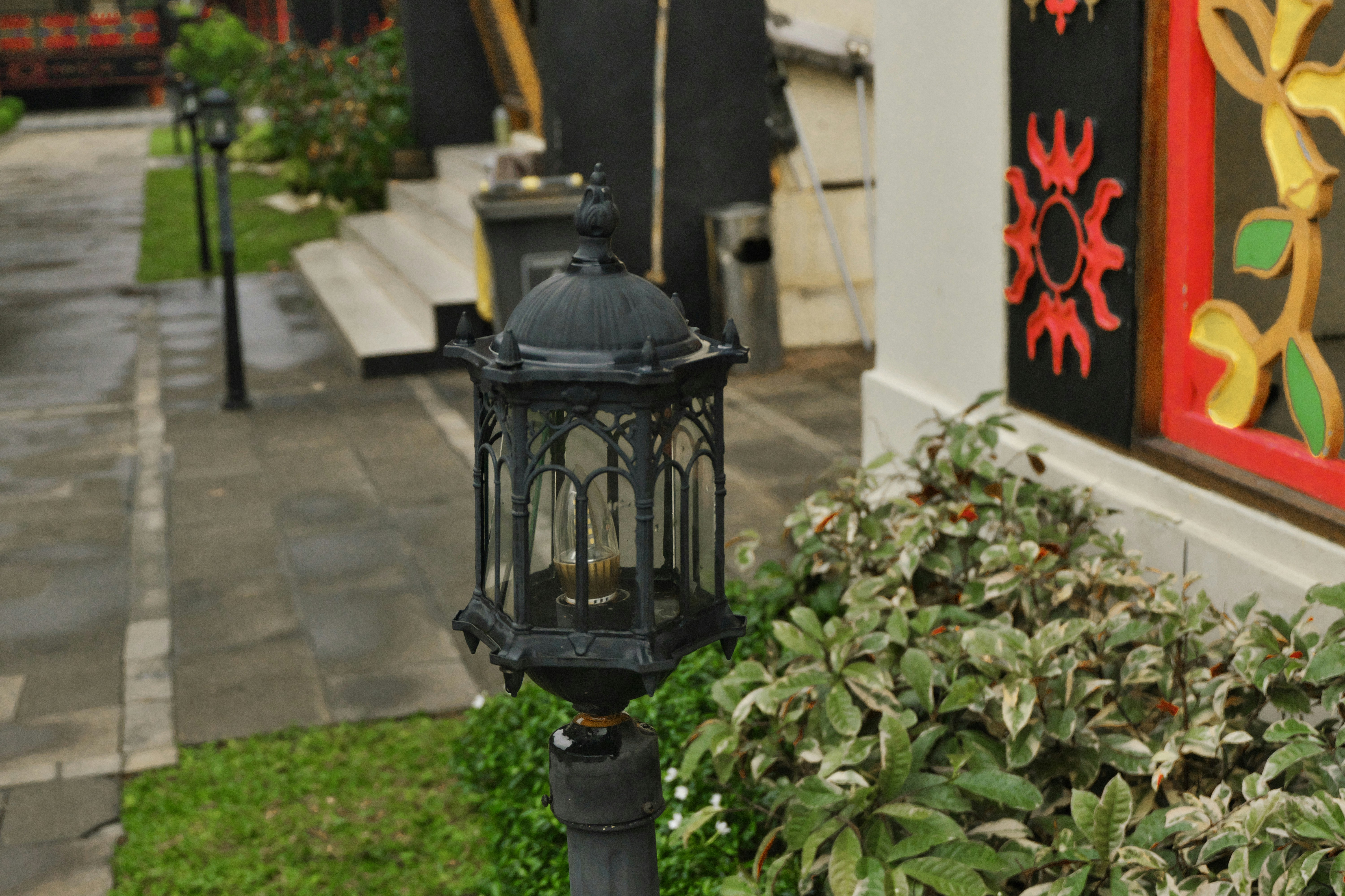 Iron Lantern on a Stone Path, Framed by Colorful Window Panels