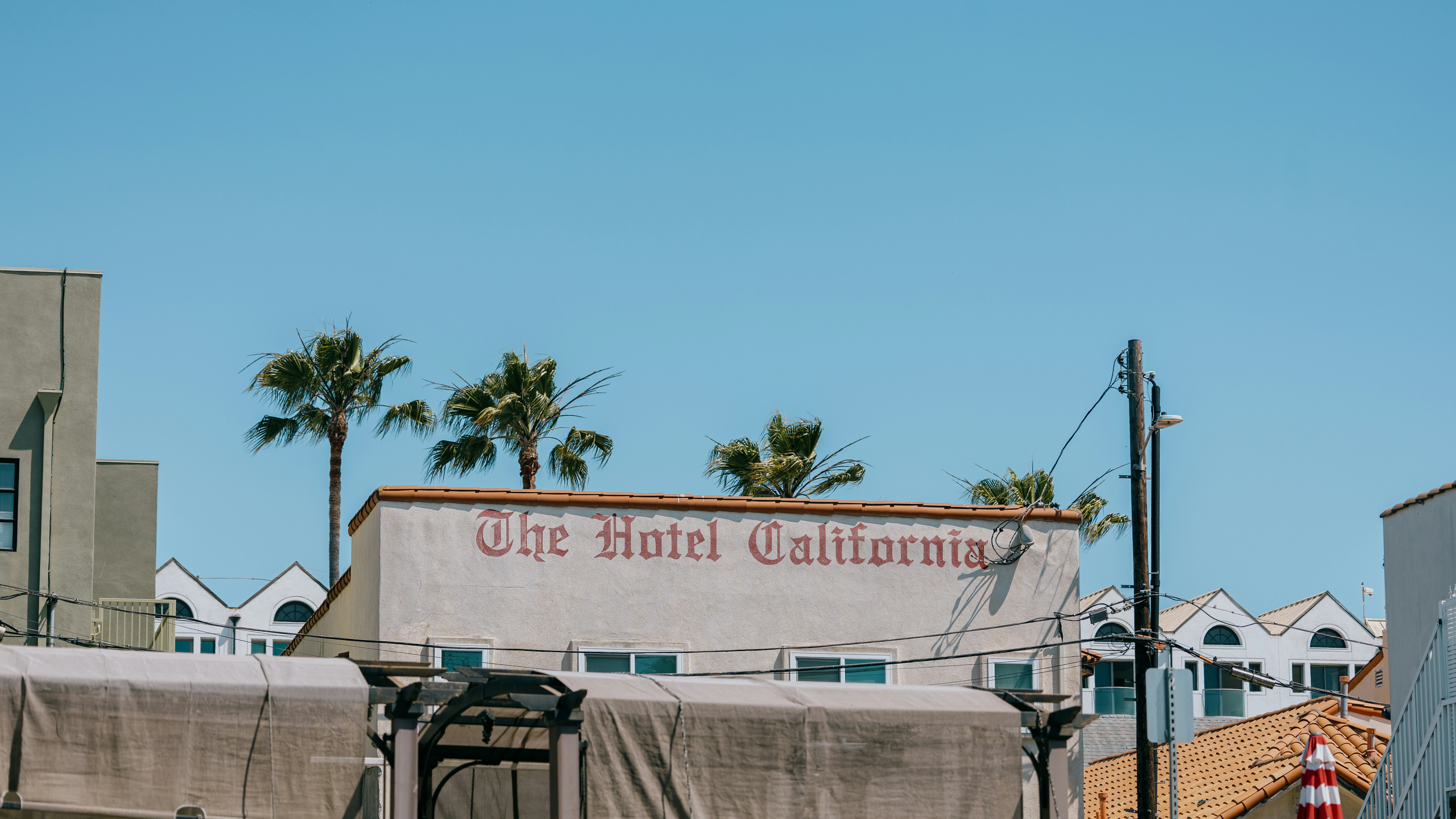 The Hotel California Sign Above a Sunlit Trolley Arcade