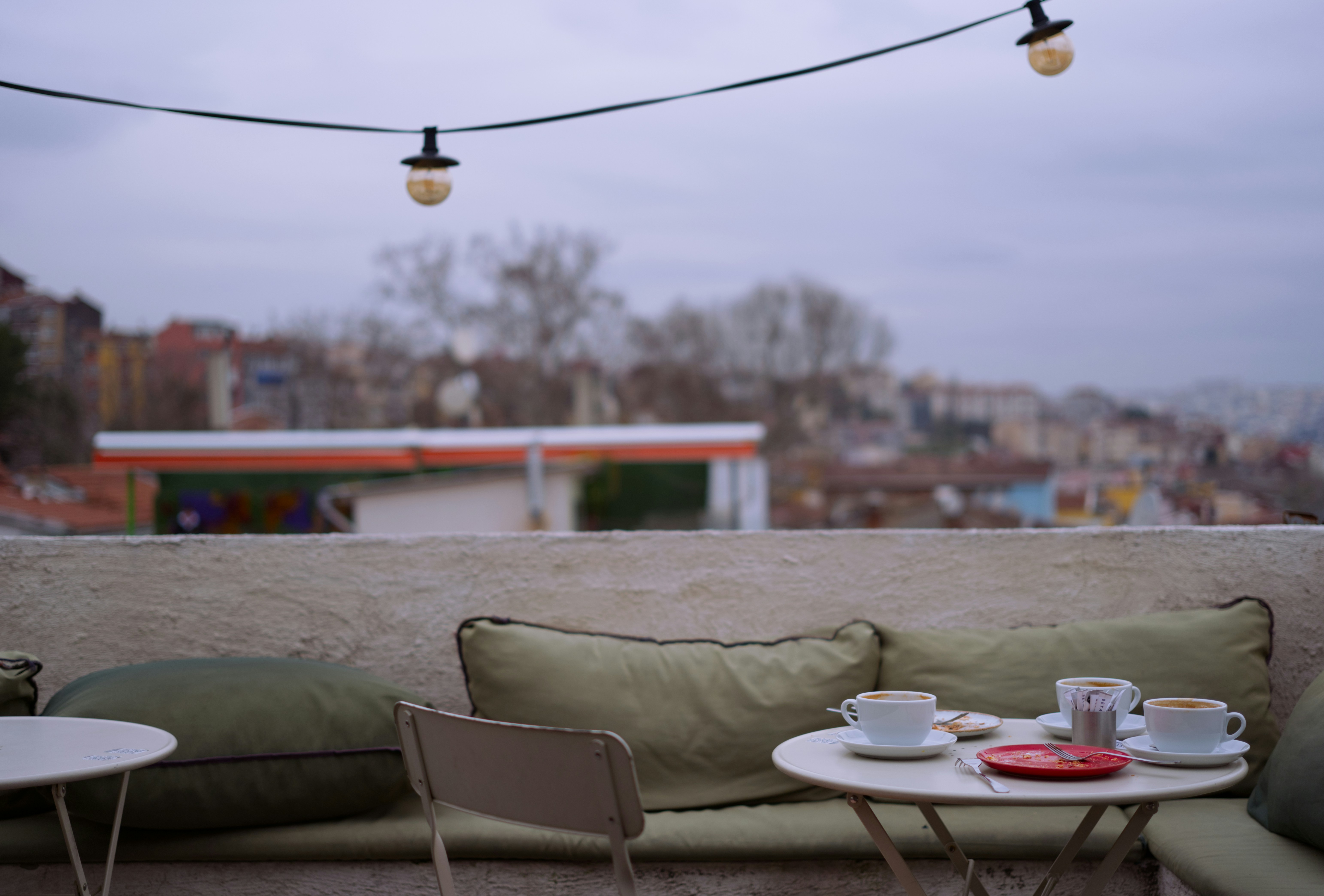 Rooftop Lounge at Dusk: Coffee, Cushions, and Gentle City Glow