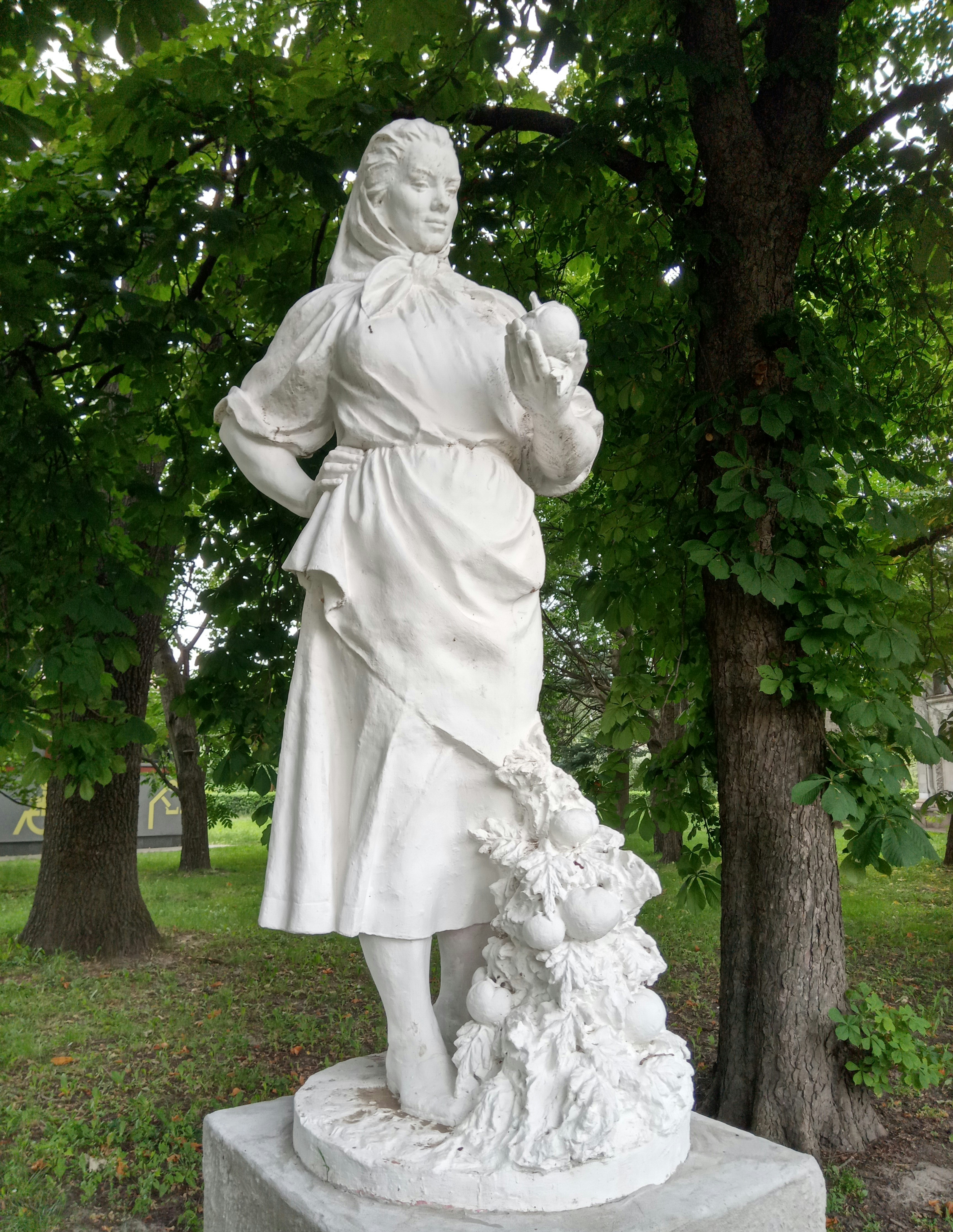 Marble Matron in the Park: A Draped Statue Framed by Green Canopy