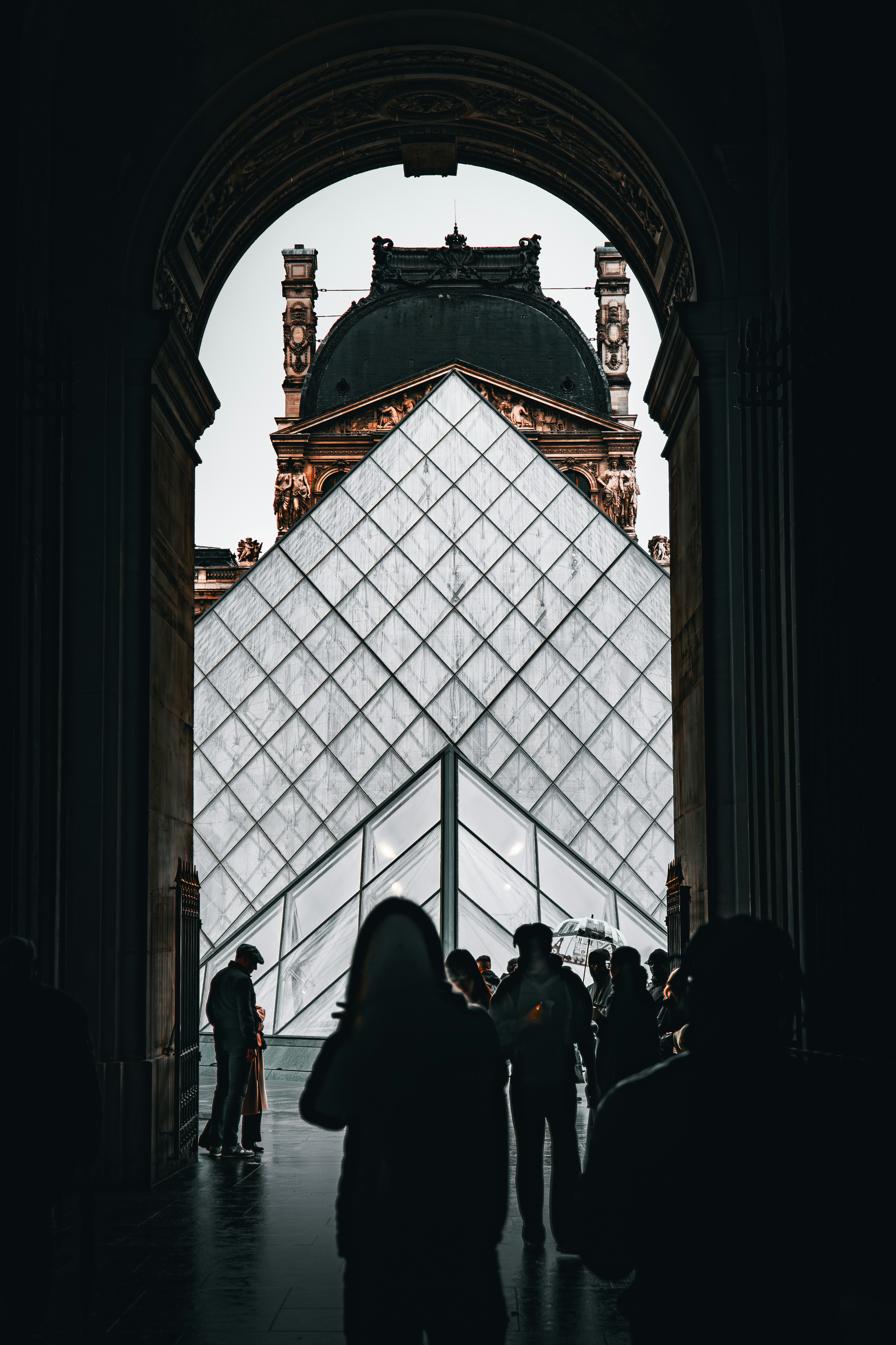 Light on Glass: People Entering the Louvre Pyramid through a Dark Arch