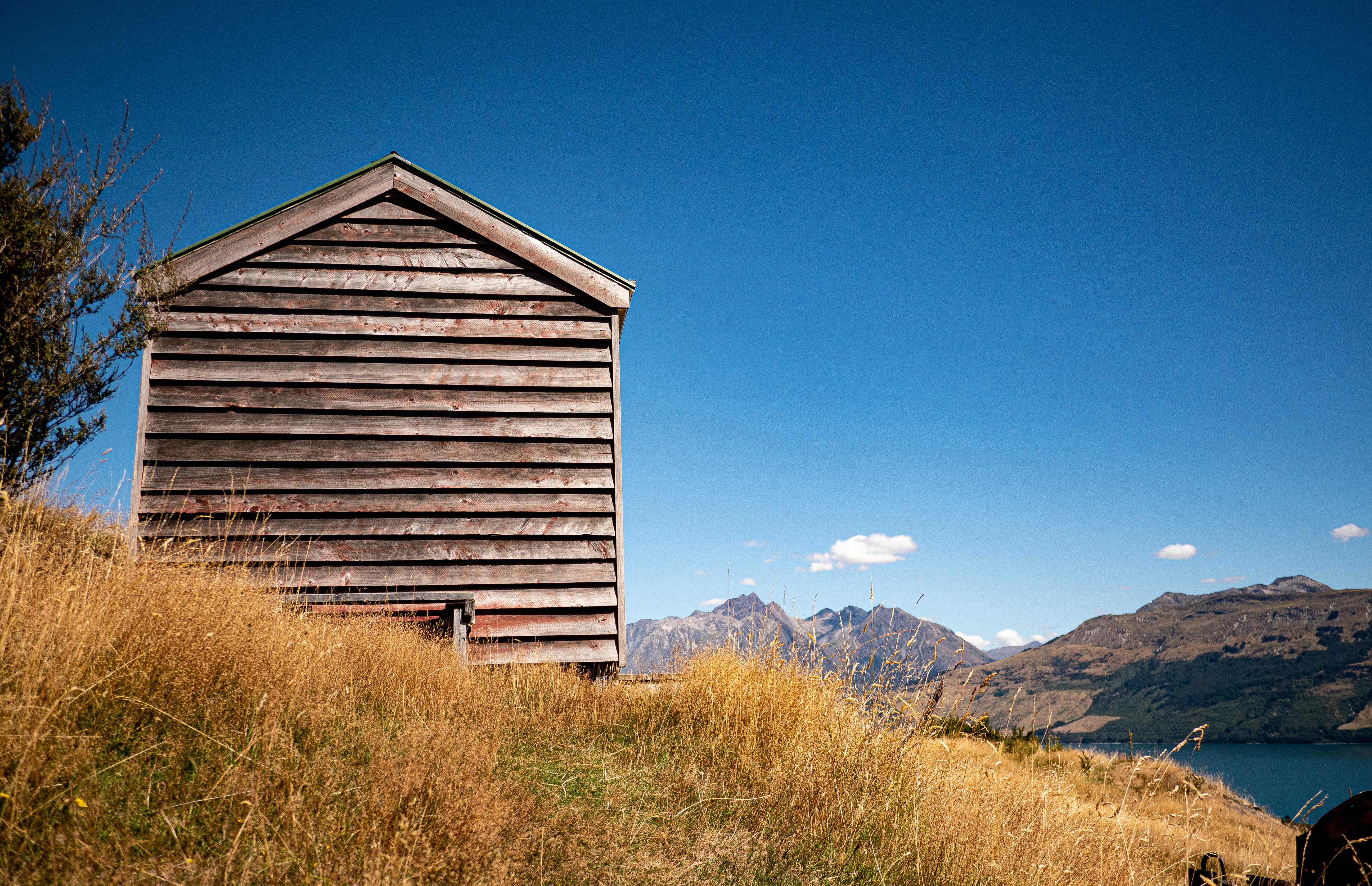 A small wooden building sitting on top of a grass covered hillside ...