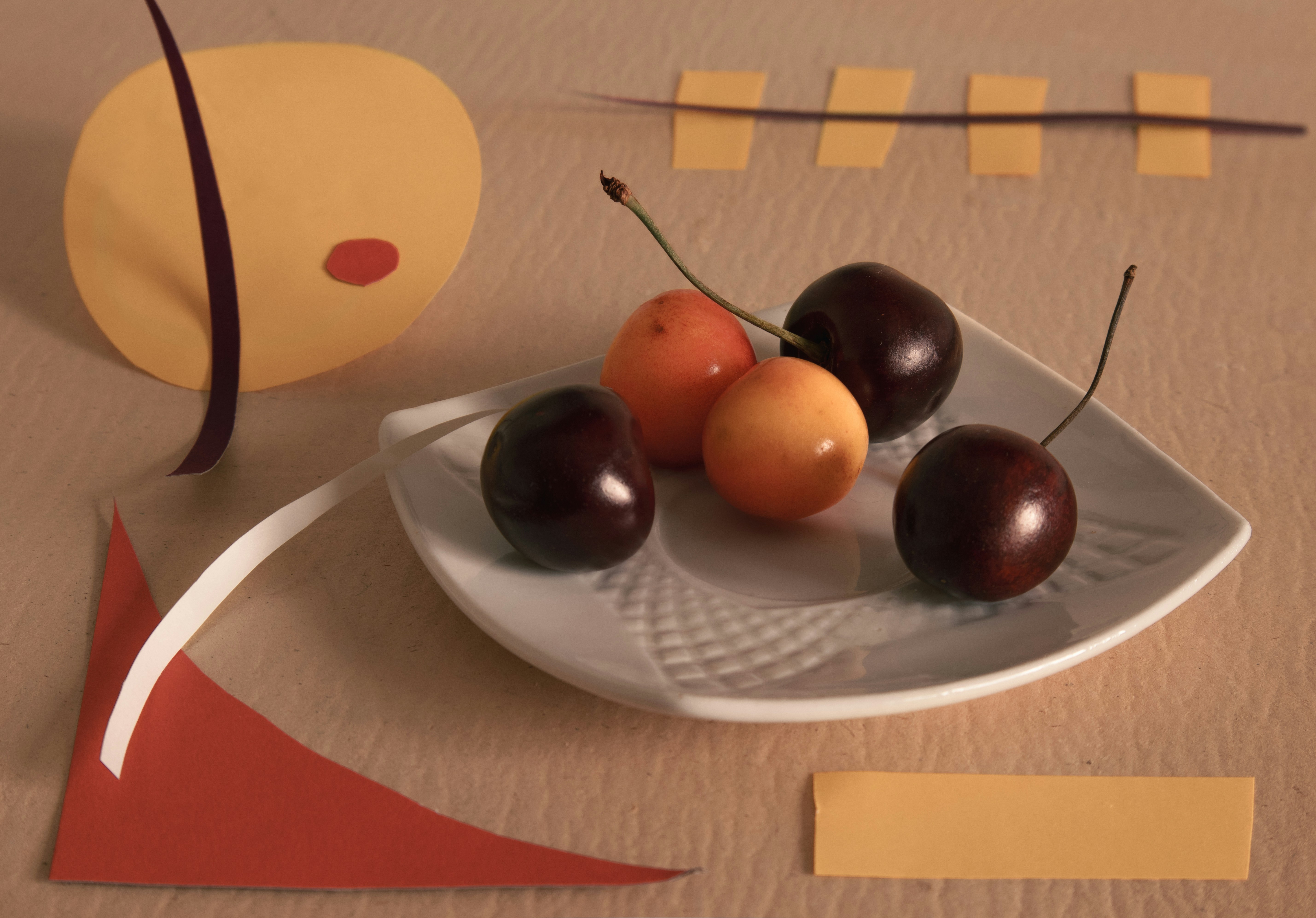 Cherries on a Leaf Plate Beneath a Playful Patchwork of Paper Shapes