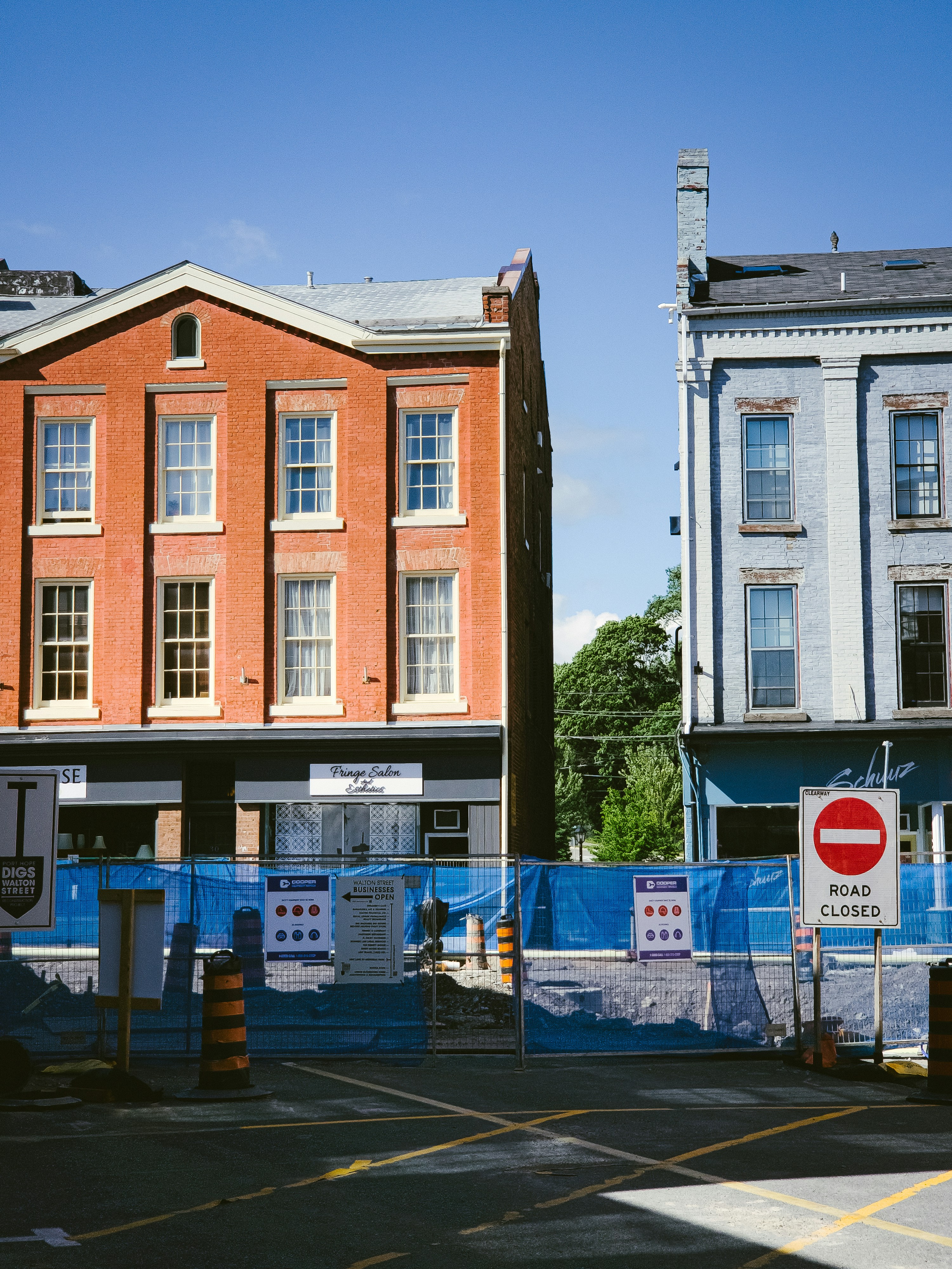 Brick Facades and a Blue Barrier: Street Scene Behind Construction Fencing