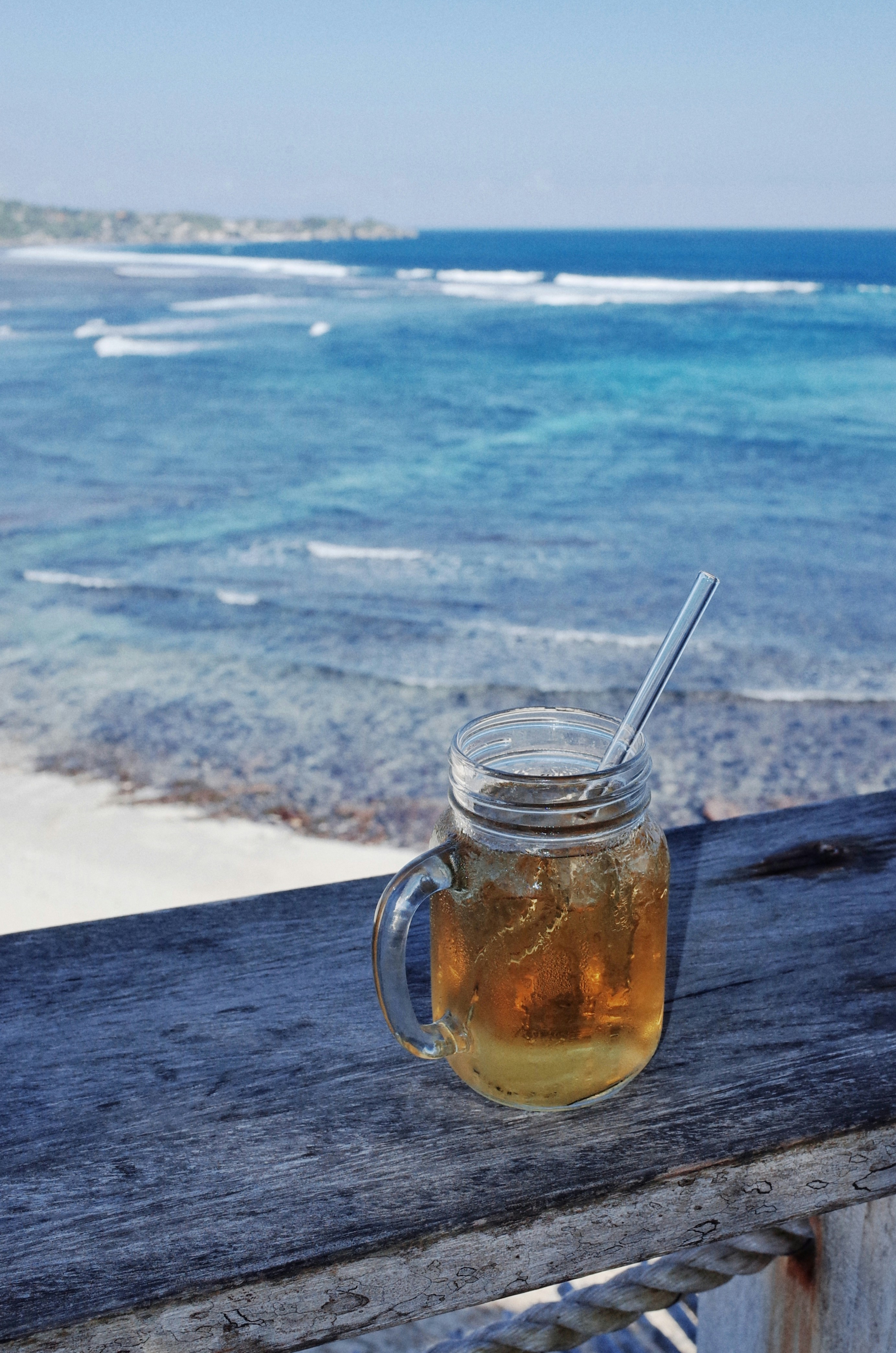 Sunlit Mason Jar on a Weathered Rail Over Turquoise Seas