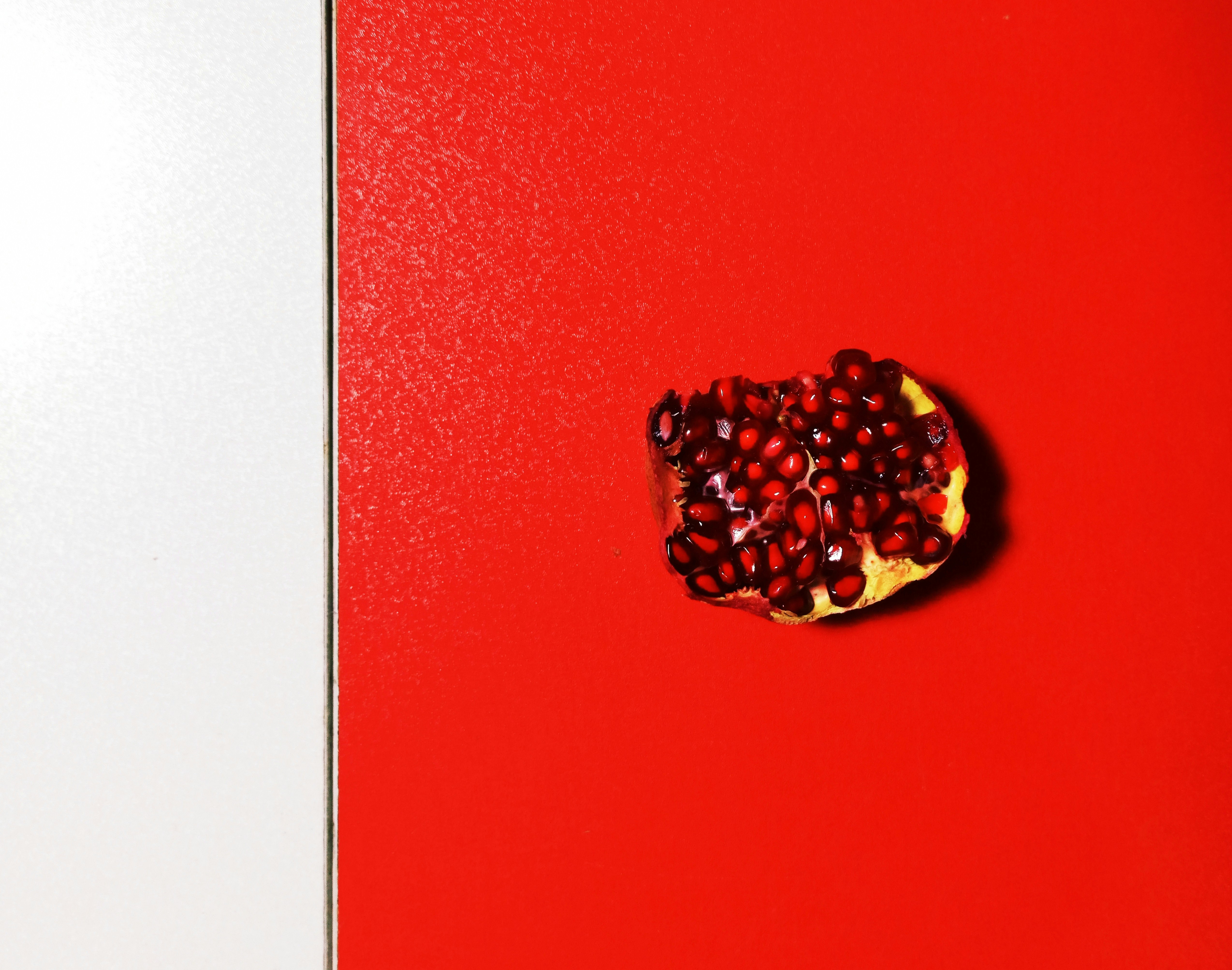 A pomegranate on a red and white surface photo – Free Food Image on Unsplash