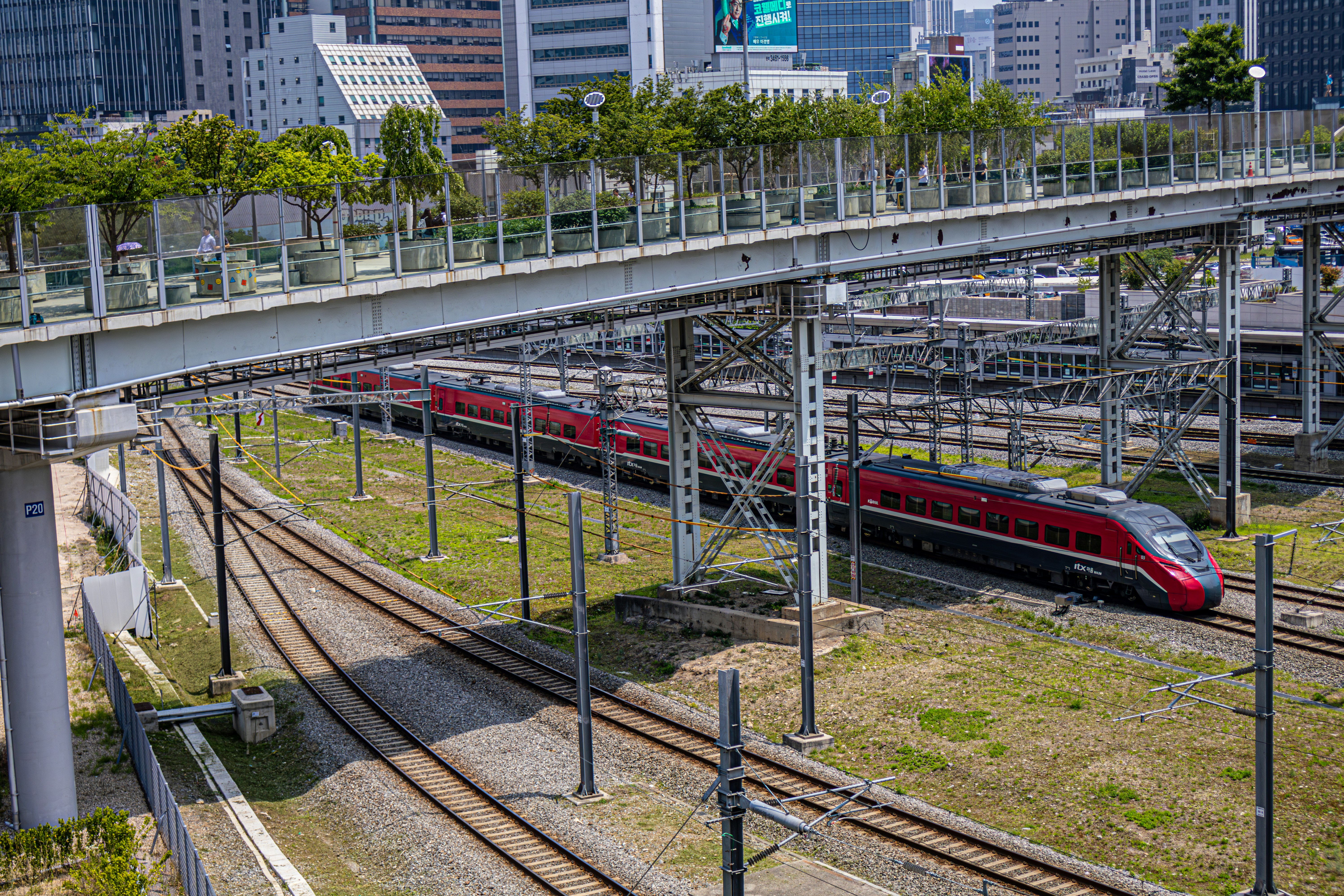 Un tren rojo viajando por las vías del tren junto a edificios altos ...
