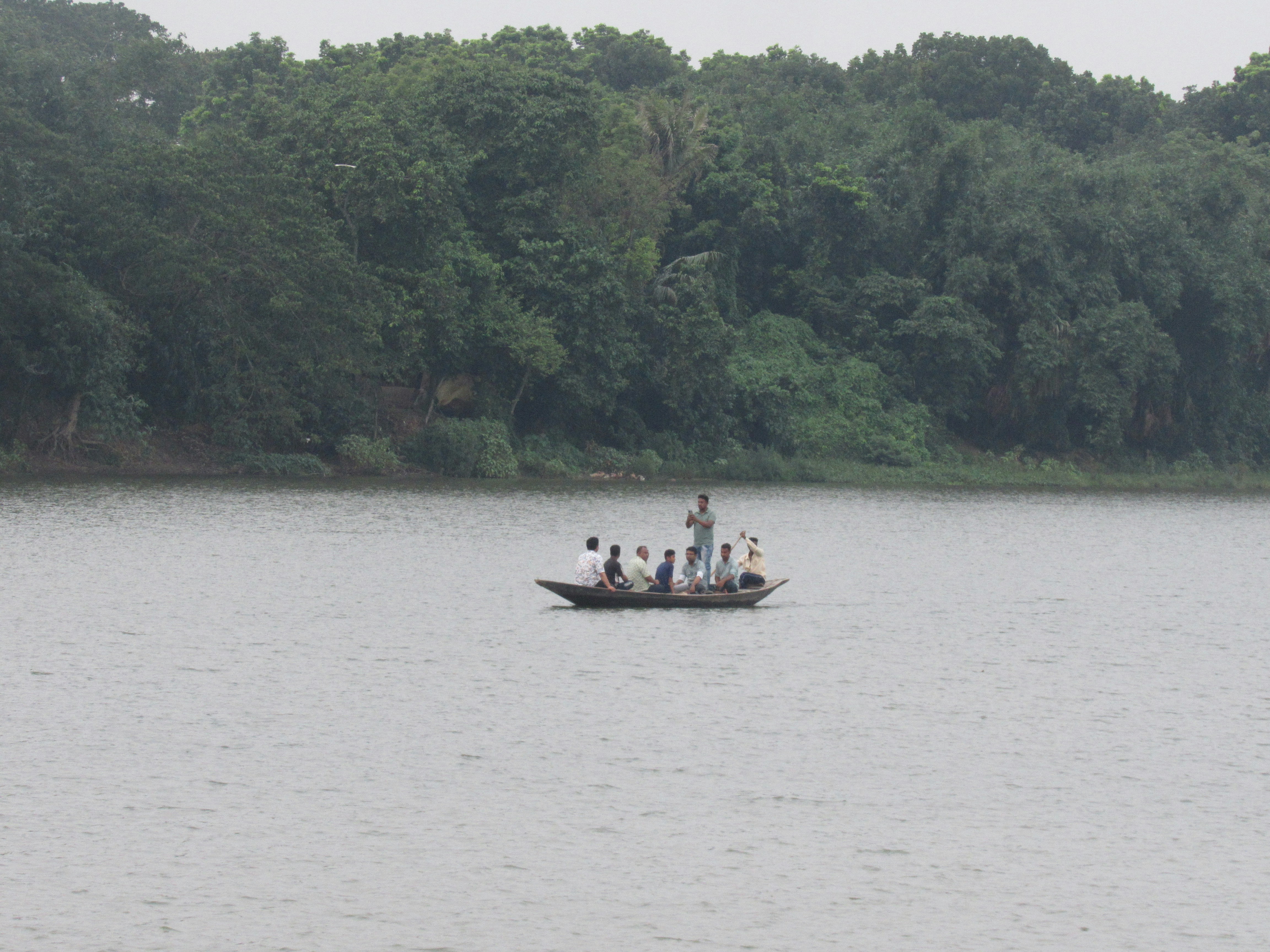 A group of people traveling on a boat across a tranquil lake, surrounded by lush greenery. The scene captures a moment of leisure and connection with nature.
