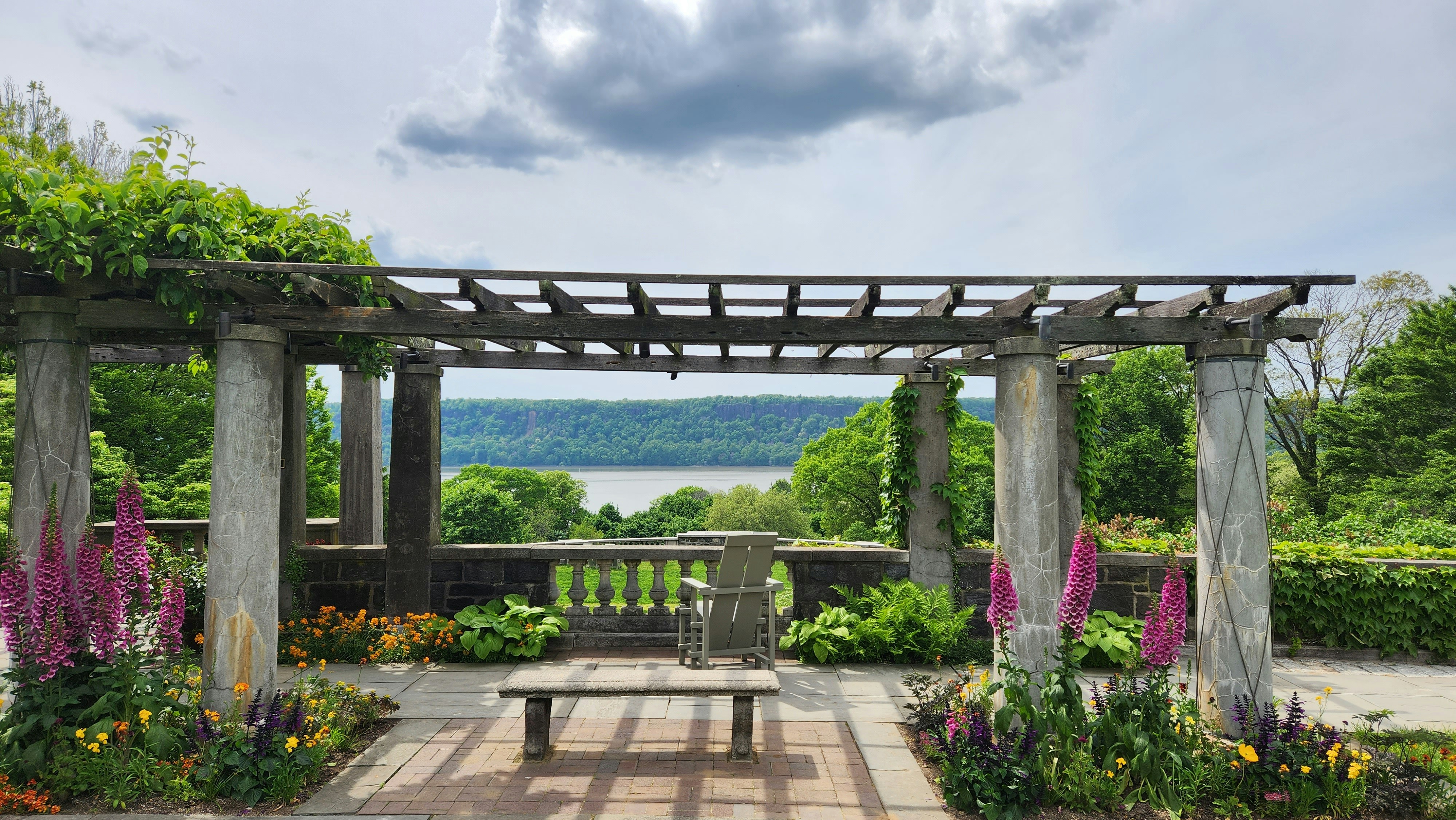 A wooden bench sitting under a pergoline covered in flowers