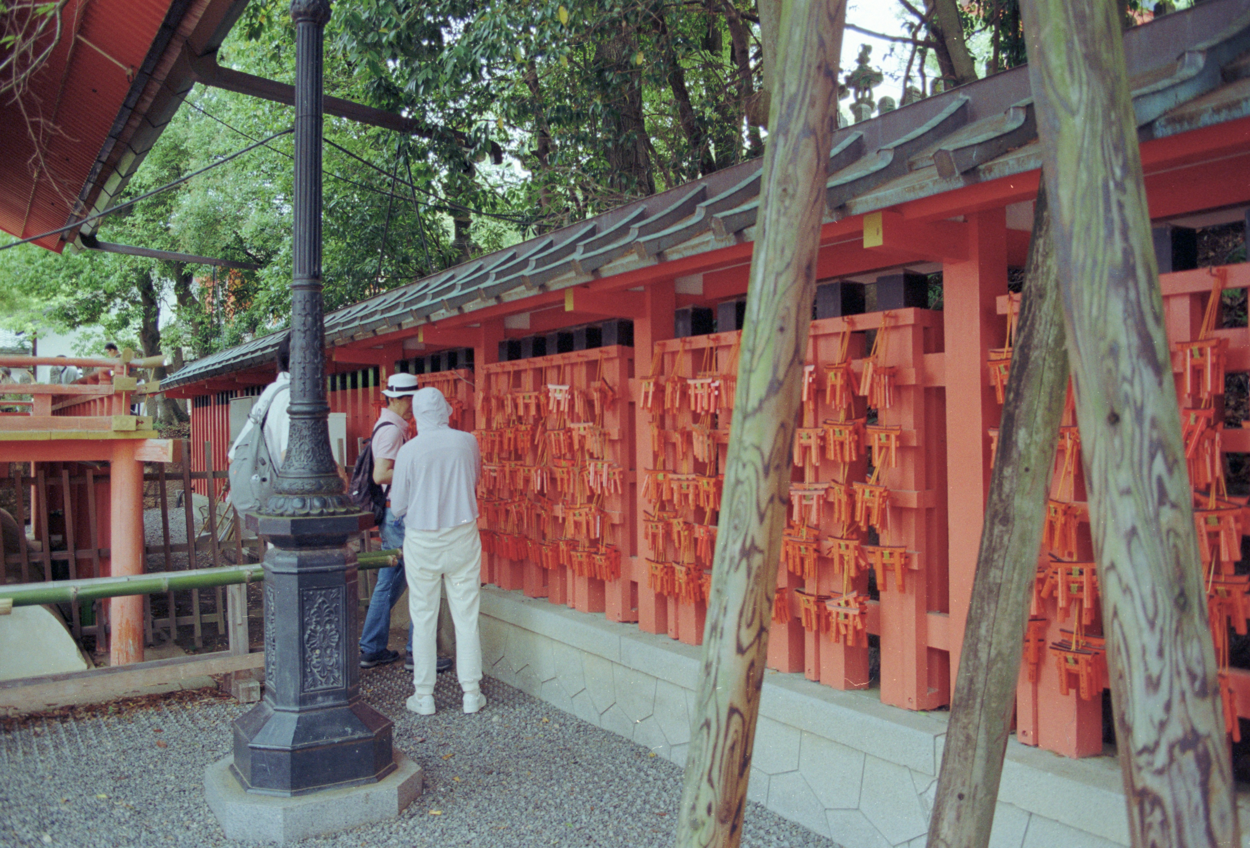 Two Visitors at the Ema Wall: Quiet Exchange Along a Crimson Shrine