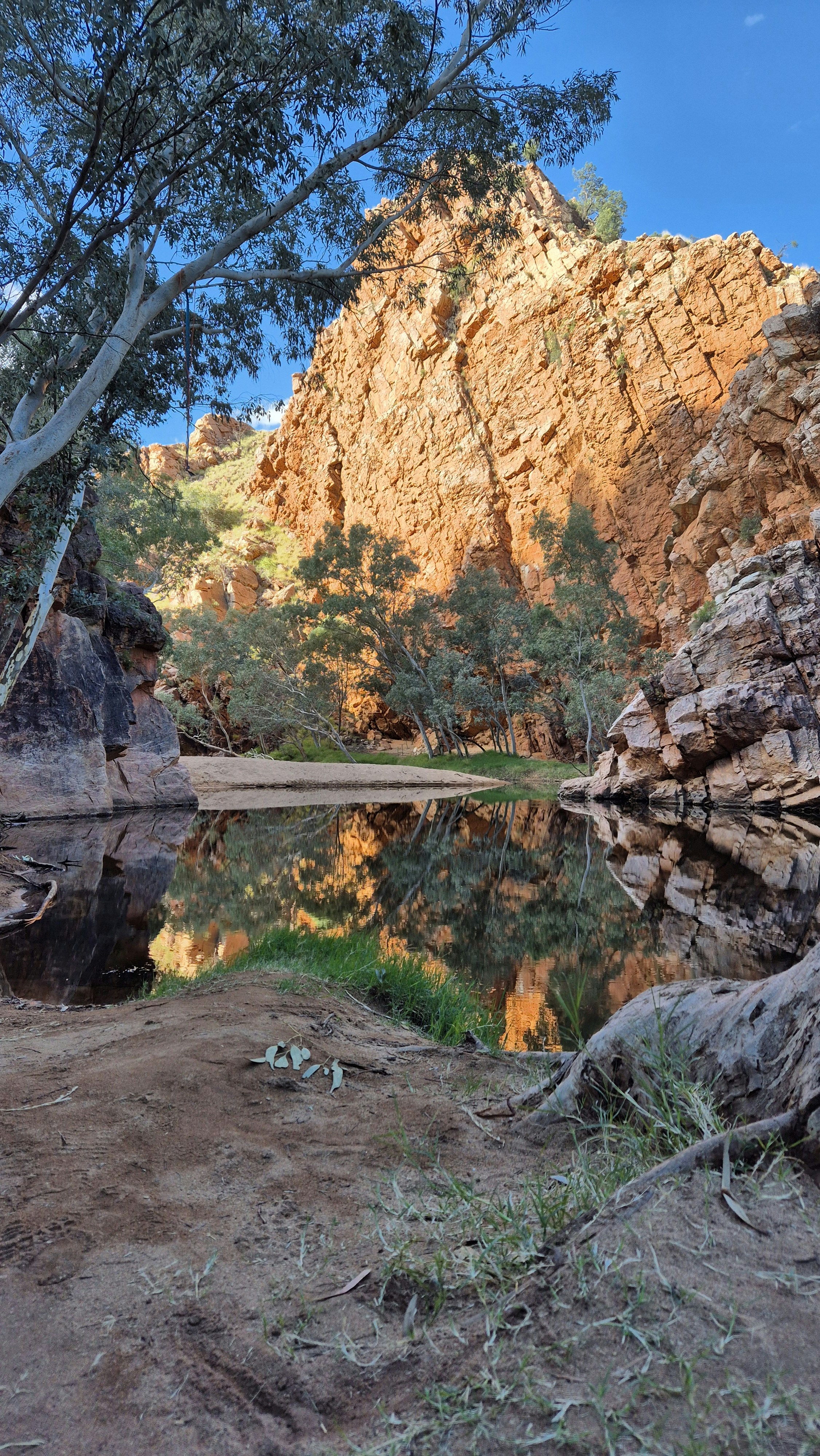A serene waterhole surrounded by rugged cliffs and lush vegetation, capturing the tranquil essence of nature's untouched beauty.