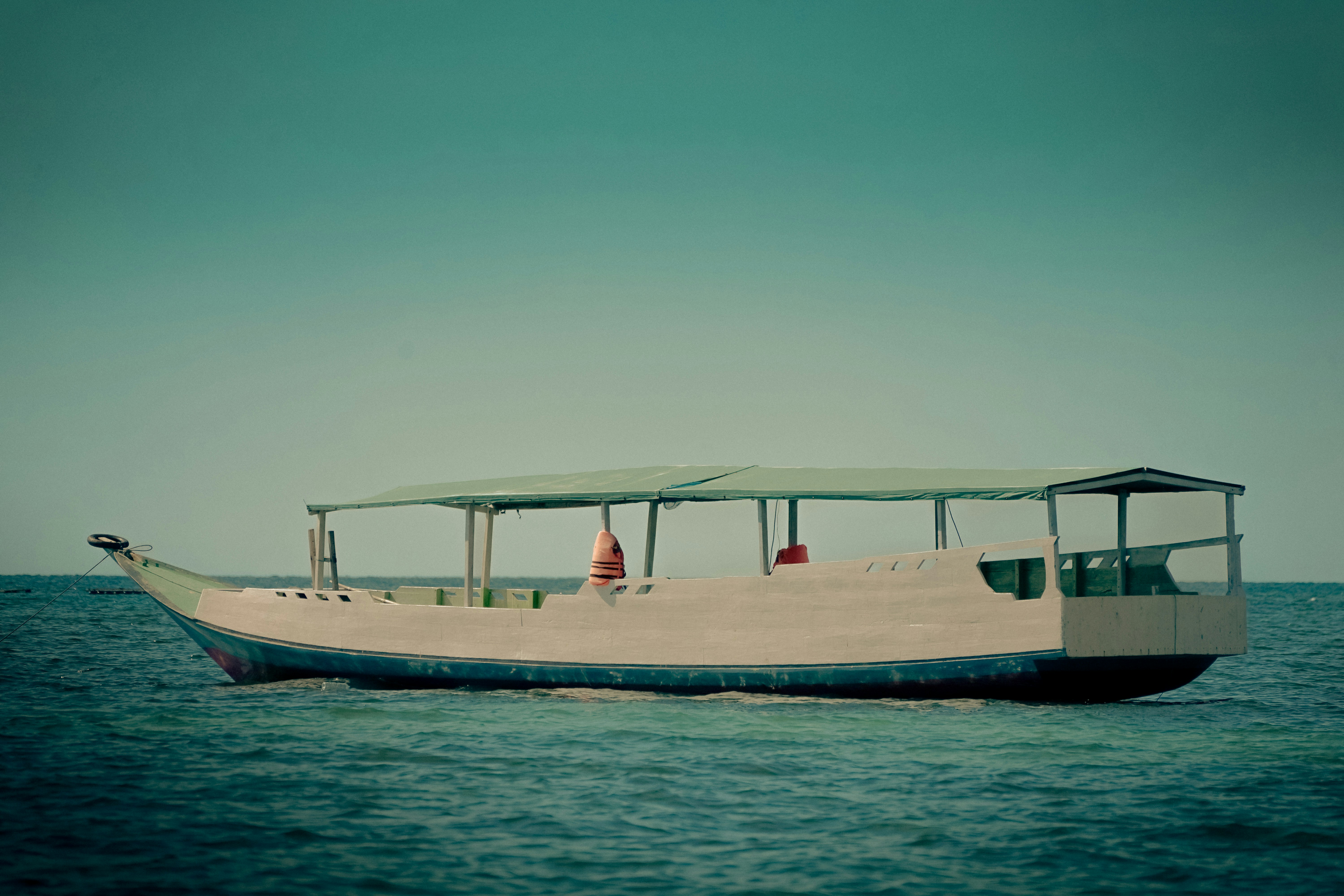 Teal Horizon: A Solitary Boat Drifts Across Quiet Seas