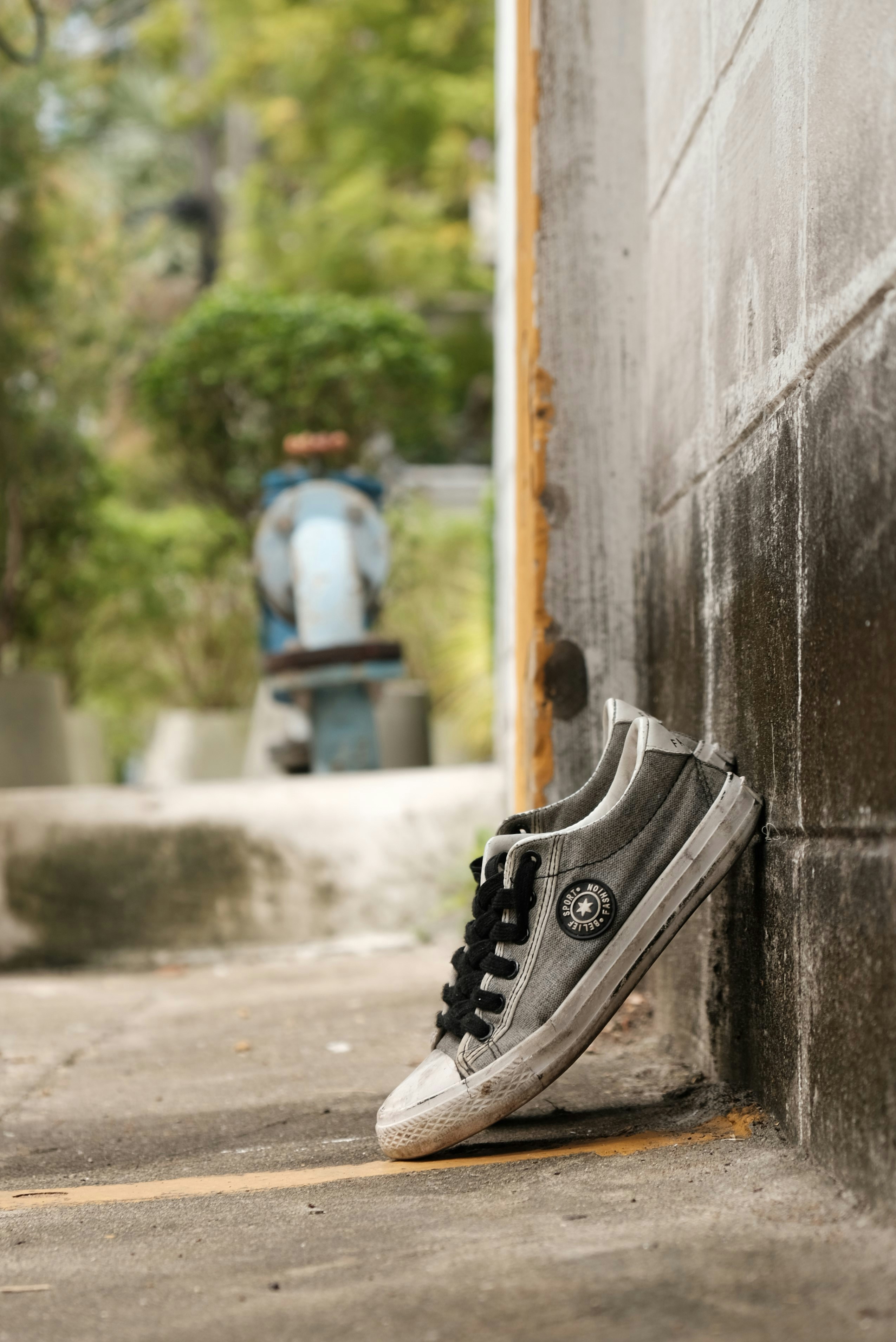 Urban Lean: A Gray Sneaker Anchored to a Weathered Wall