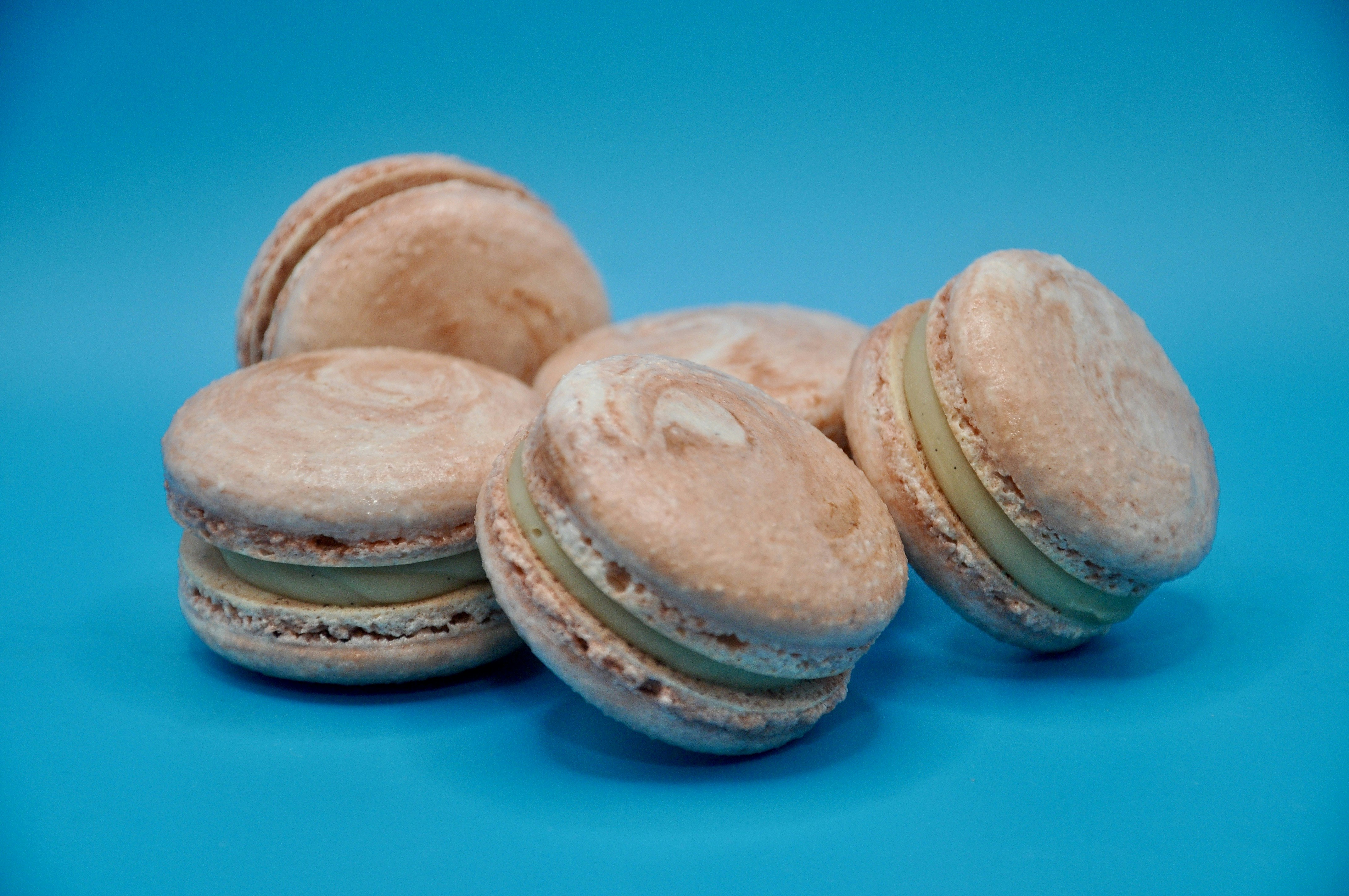 A pile of three macaroons sitting on top of a blue surface photo – Free ...