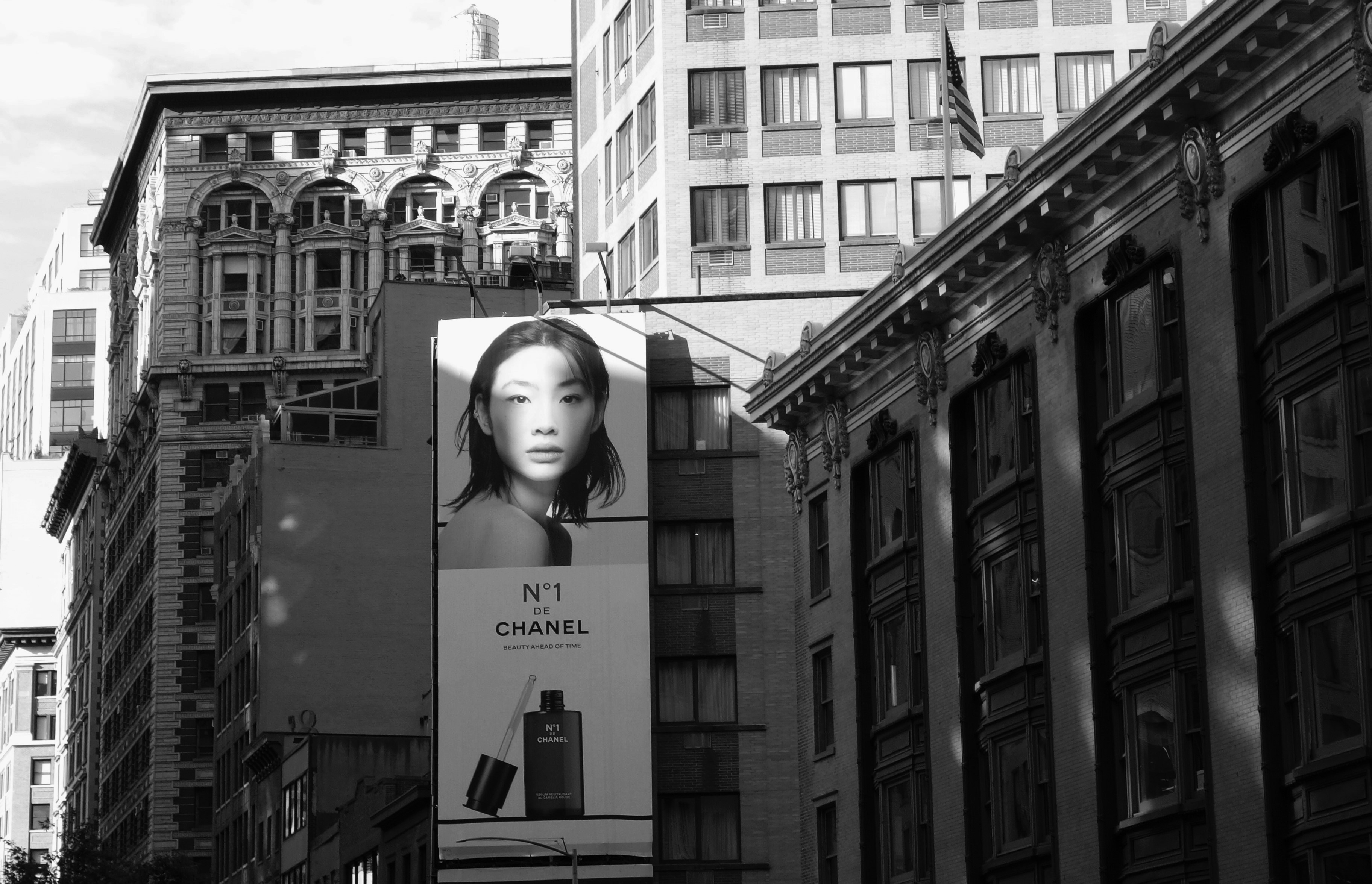 A black and white photo of a billboard on a city street