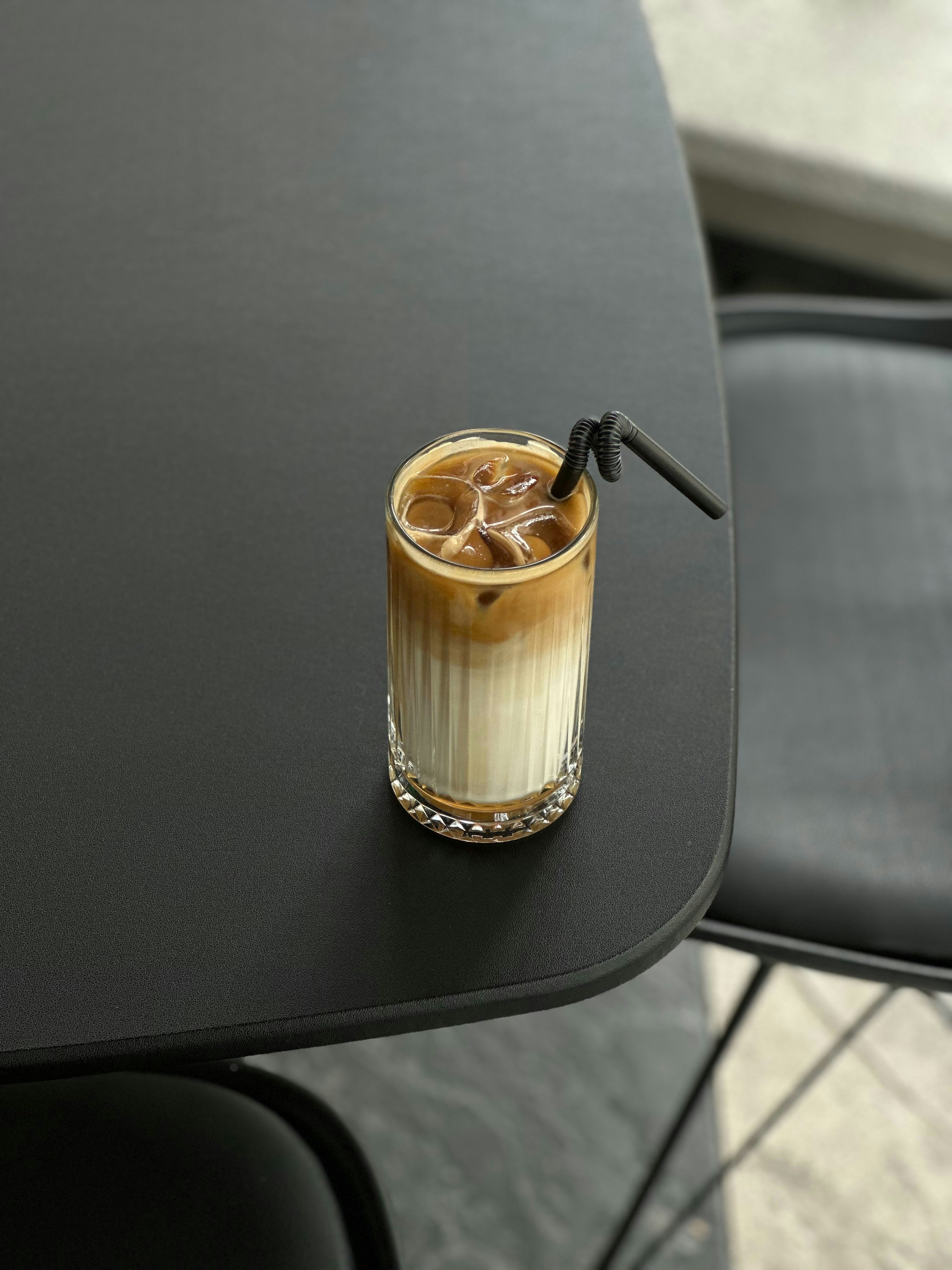 Iced Coffee in a Ribbed Glass on a Matte Black Café Table