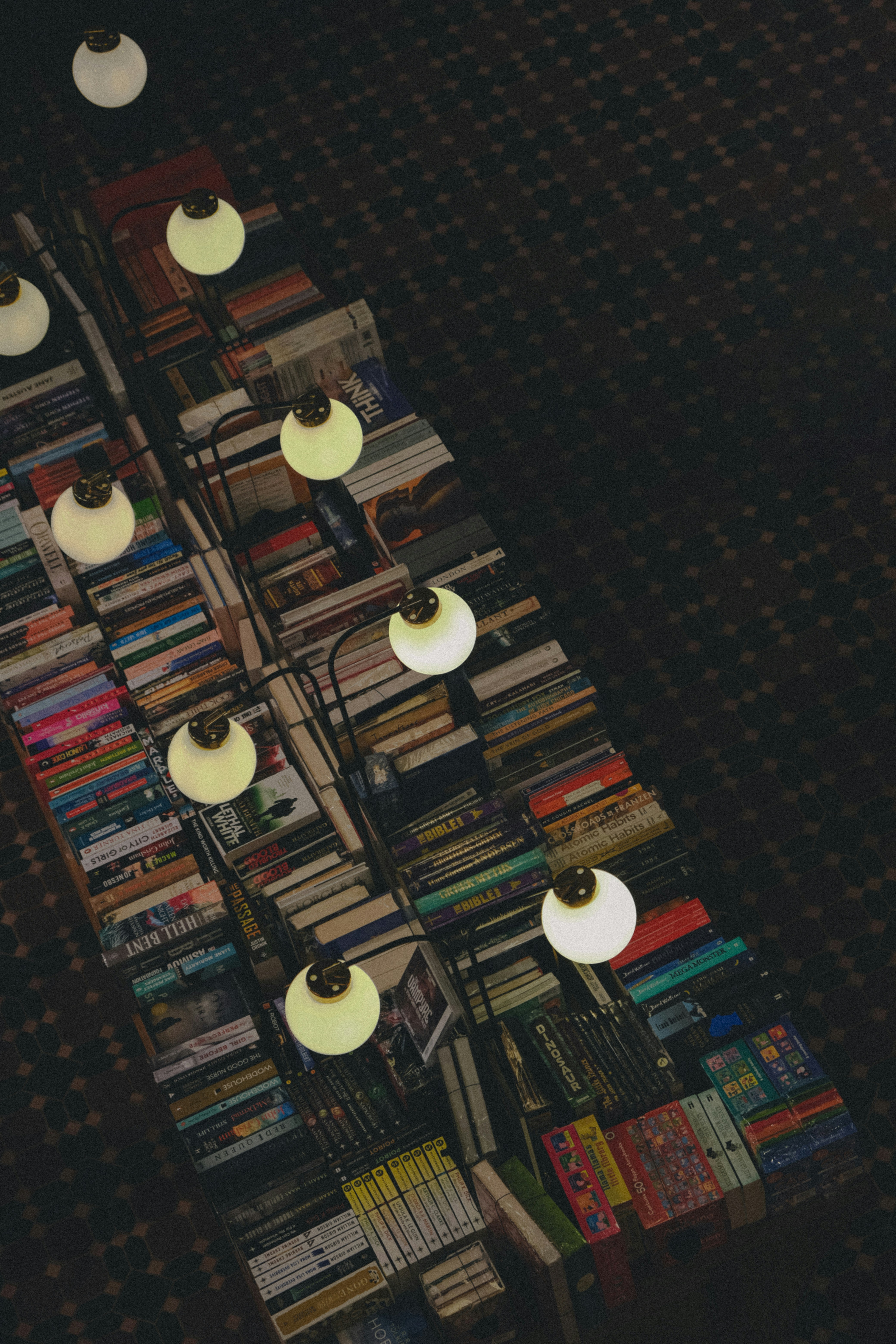 Orb-lit Aisles: A Diagonal Library Display Bathed in Warm Bulbs