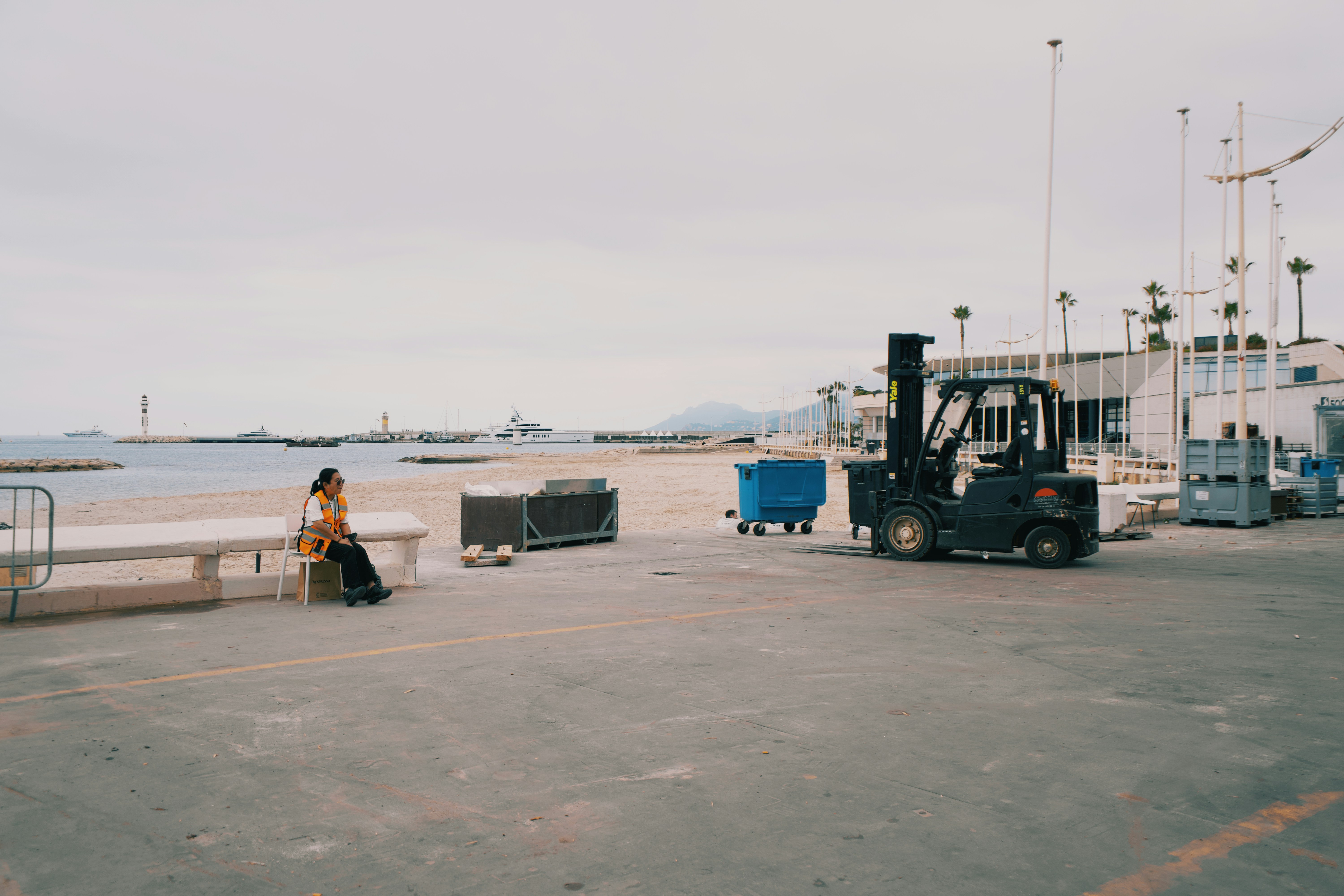 Harbor Quiet: Orange-clad Figure by the Forklift on the Dock