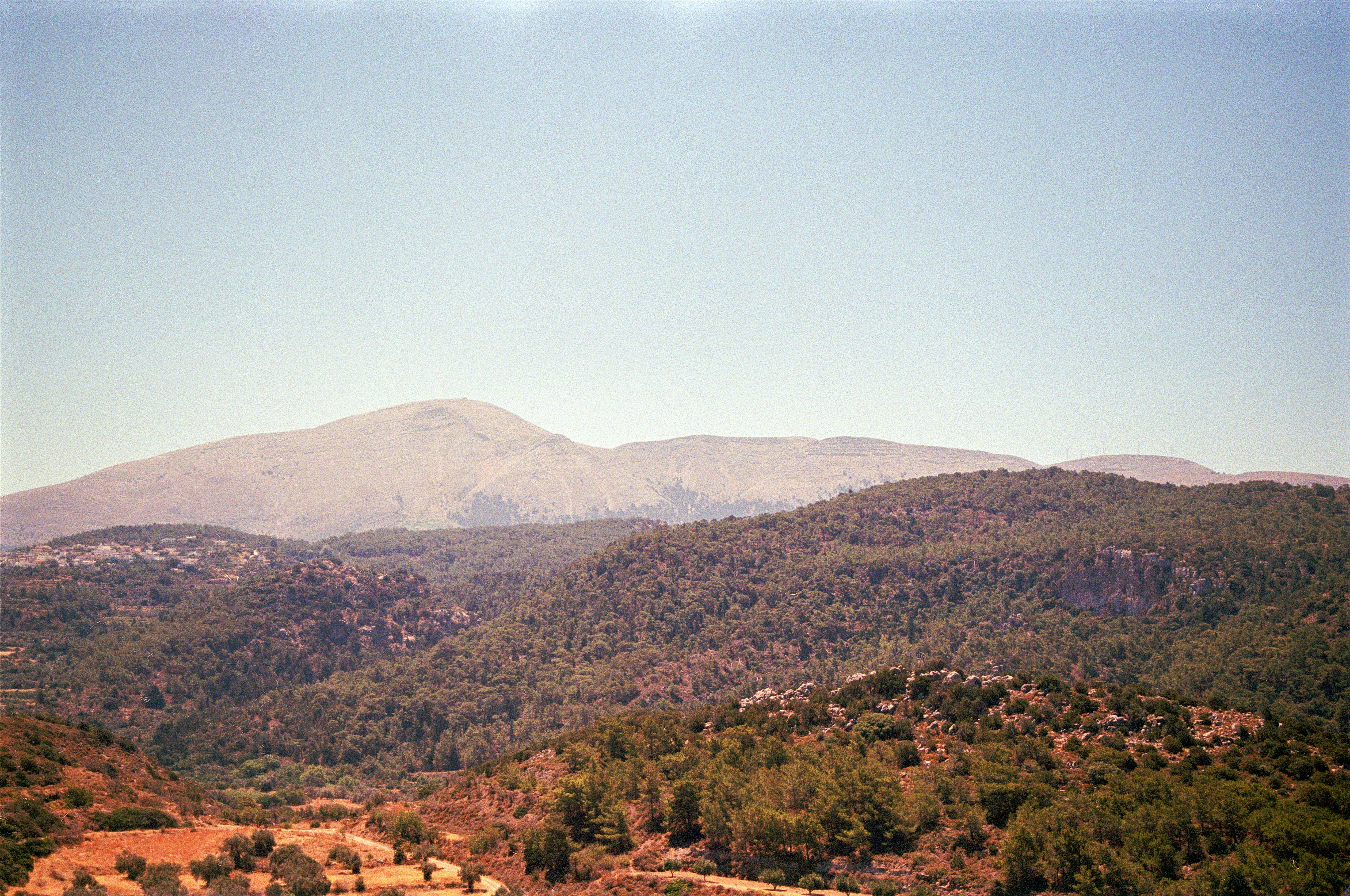 Mountain range with rolling green hills under a clear blue sky.