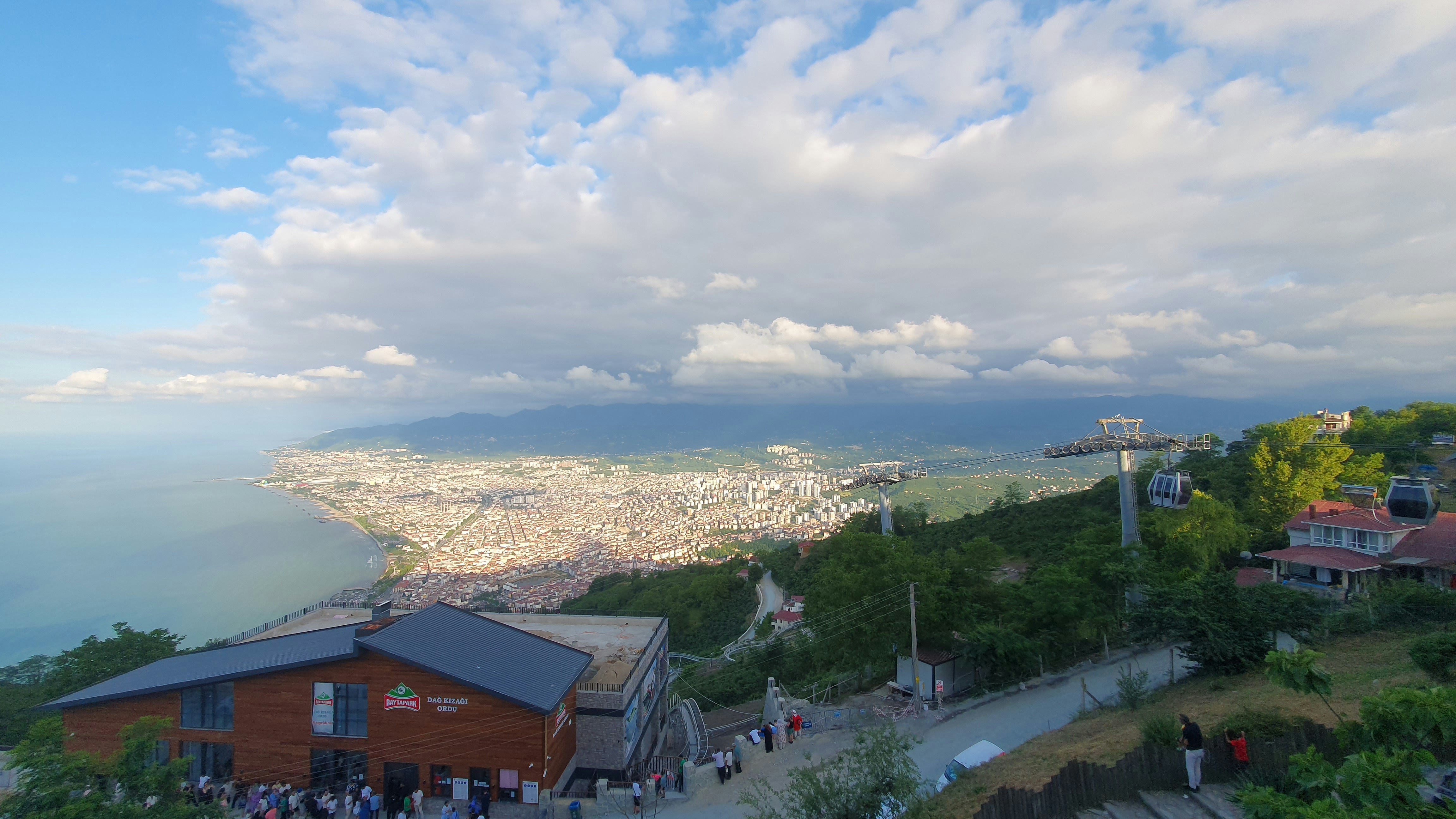 Expansive view of the Black Sea coastline intertwined with urban structures under a clouded sky.