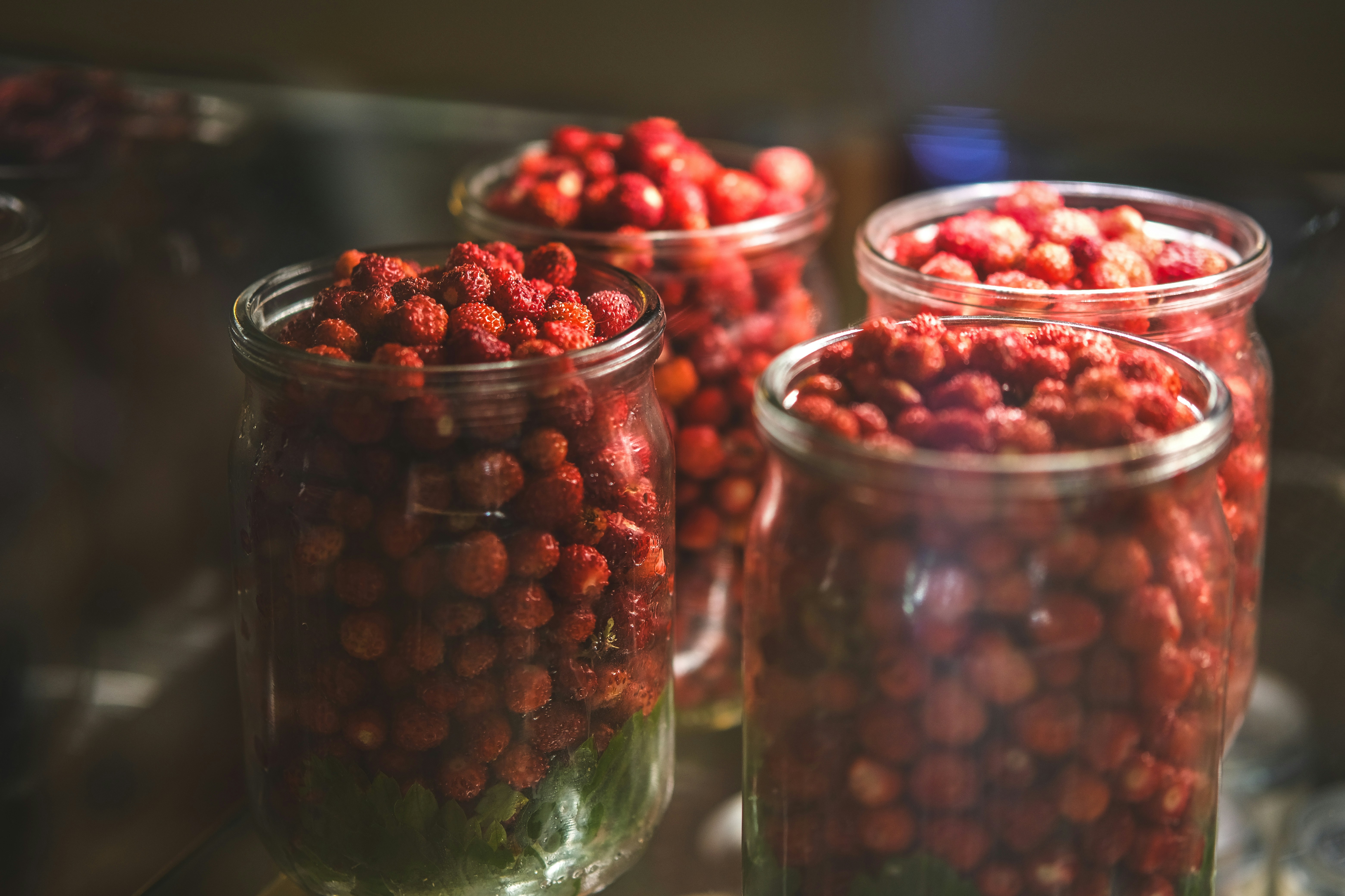 Crimson Harvest in Glass: Berry-Filled Jars Glow Under Soft Refrigerator Light