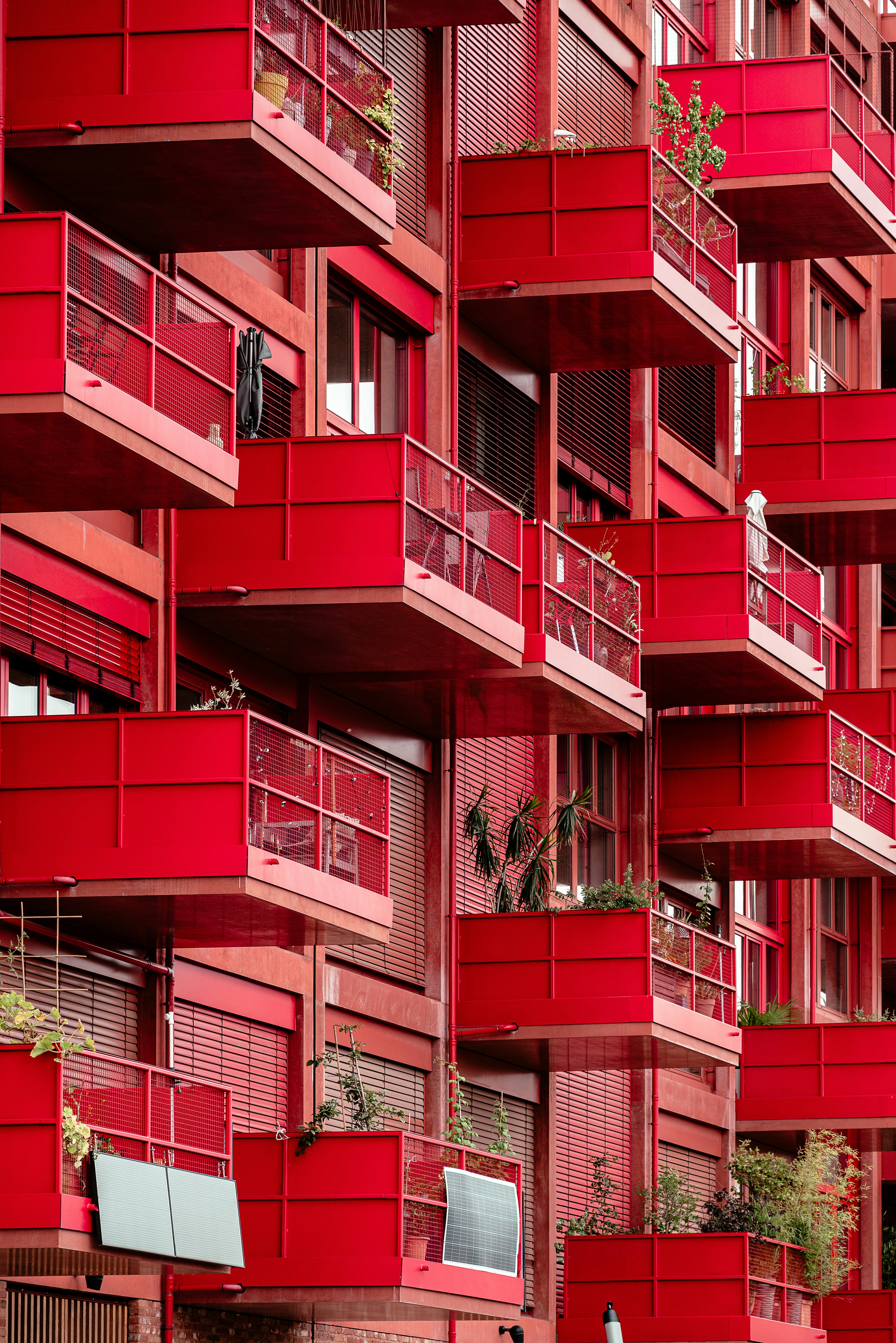 A red building with balconies and plants on the balconies photo – Free ...