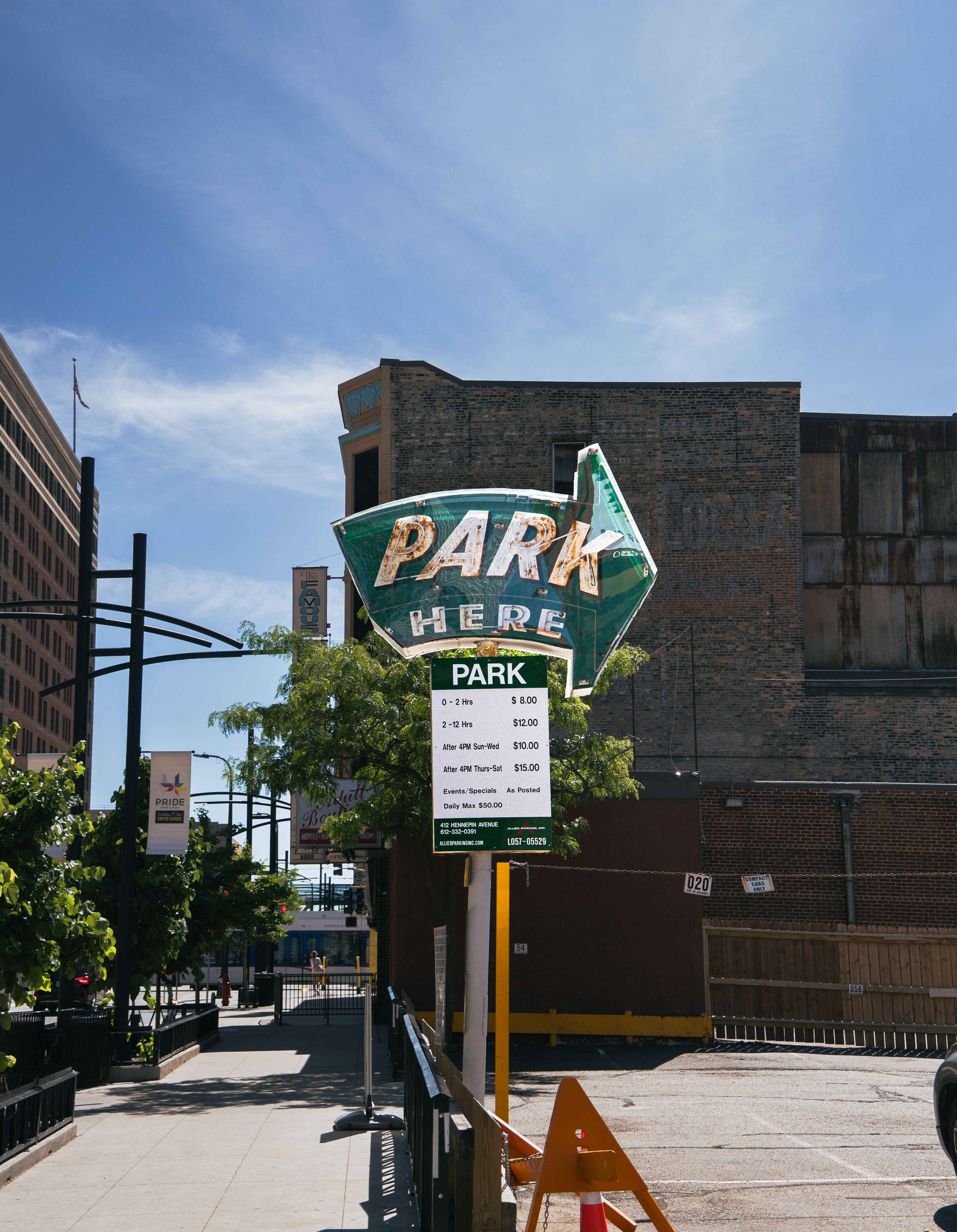 Park Here in Neon: A Sunlit Street Sign Anchoring the City Block