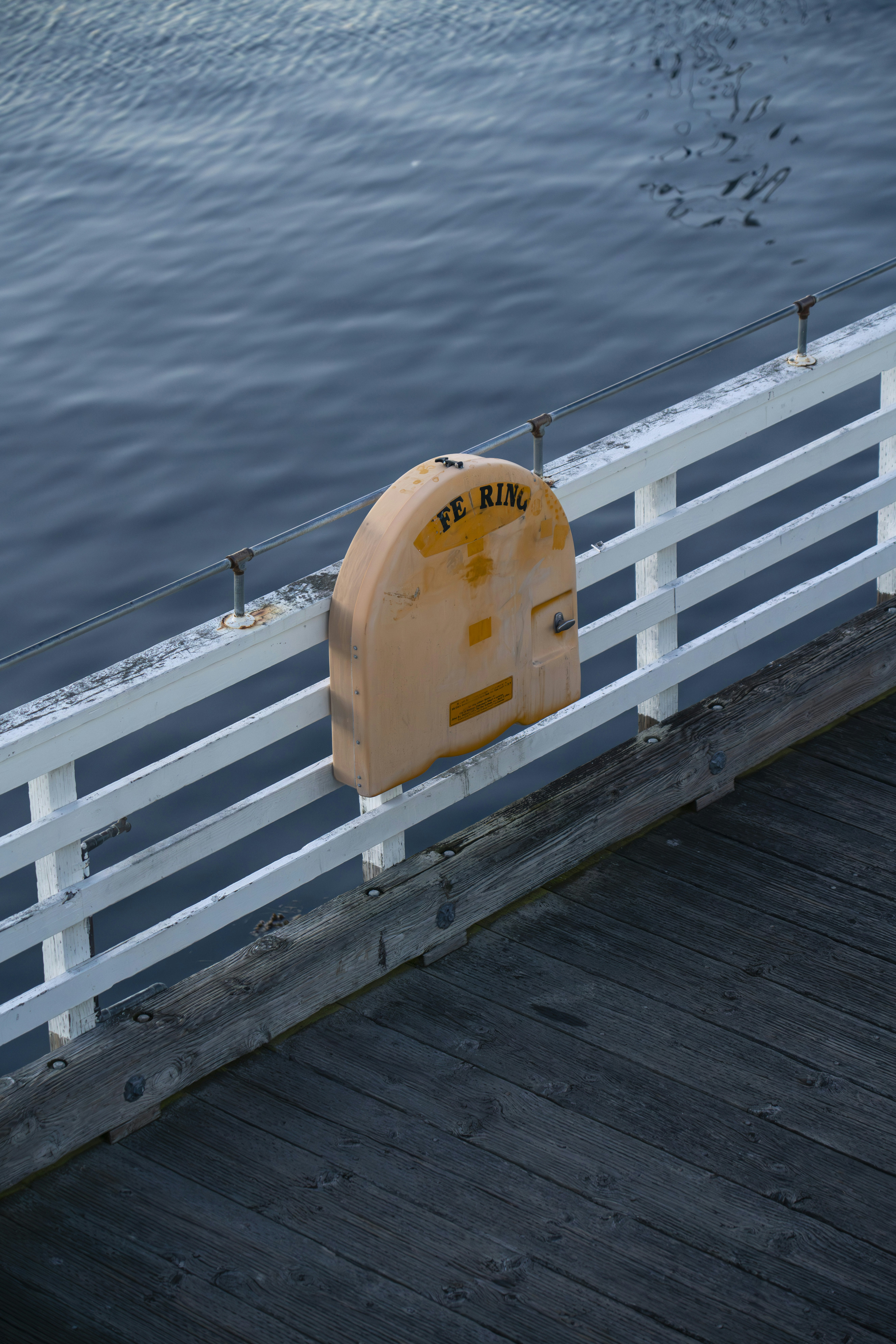 Weathered Yellow Rescue Box Clinging to a Quiet Pier Rail