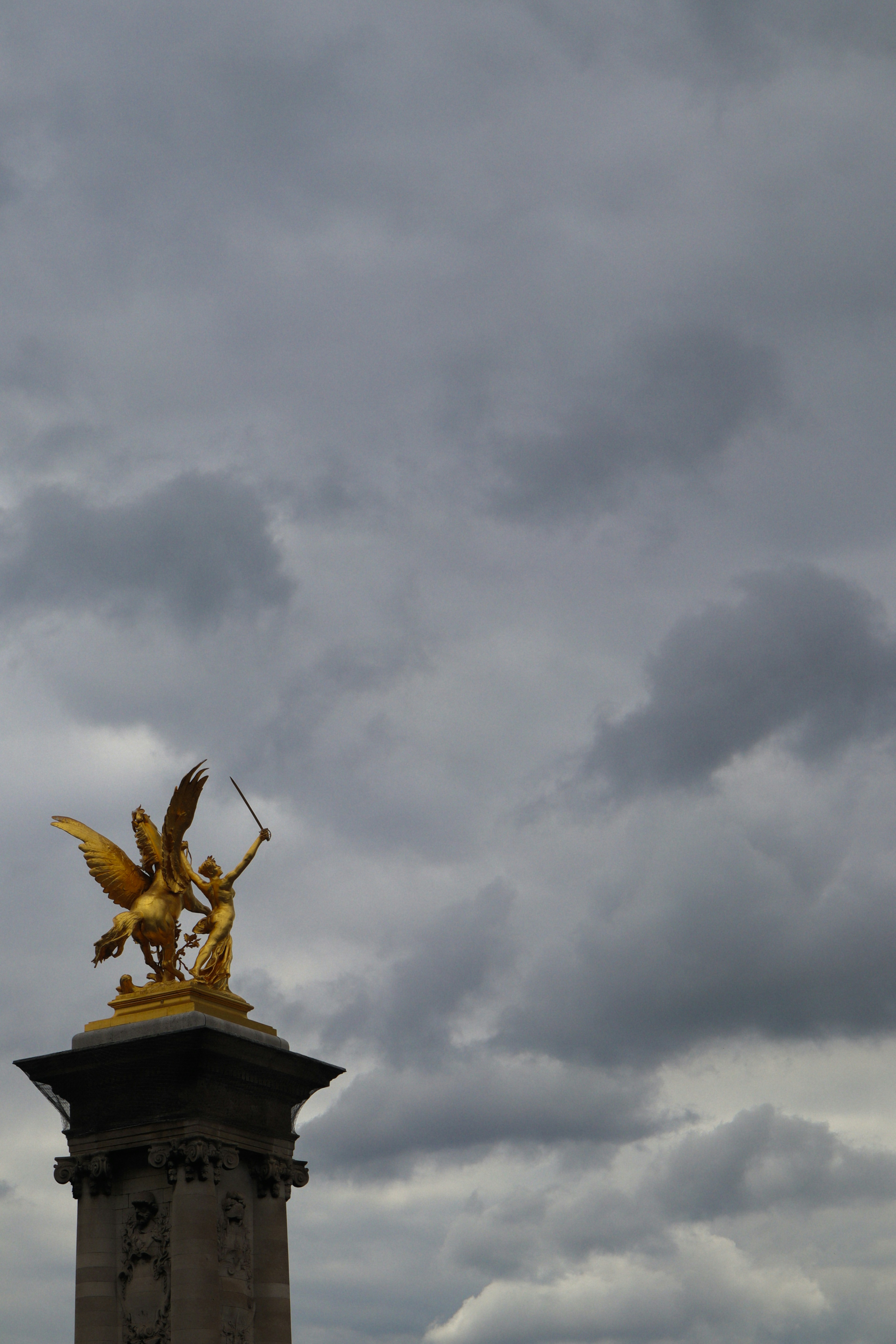 Golden Winged Triumph on a Dark Pedestal Beneath a Brooding Sky