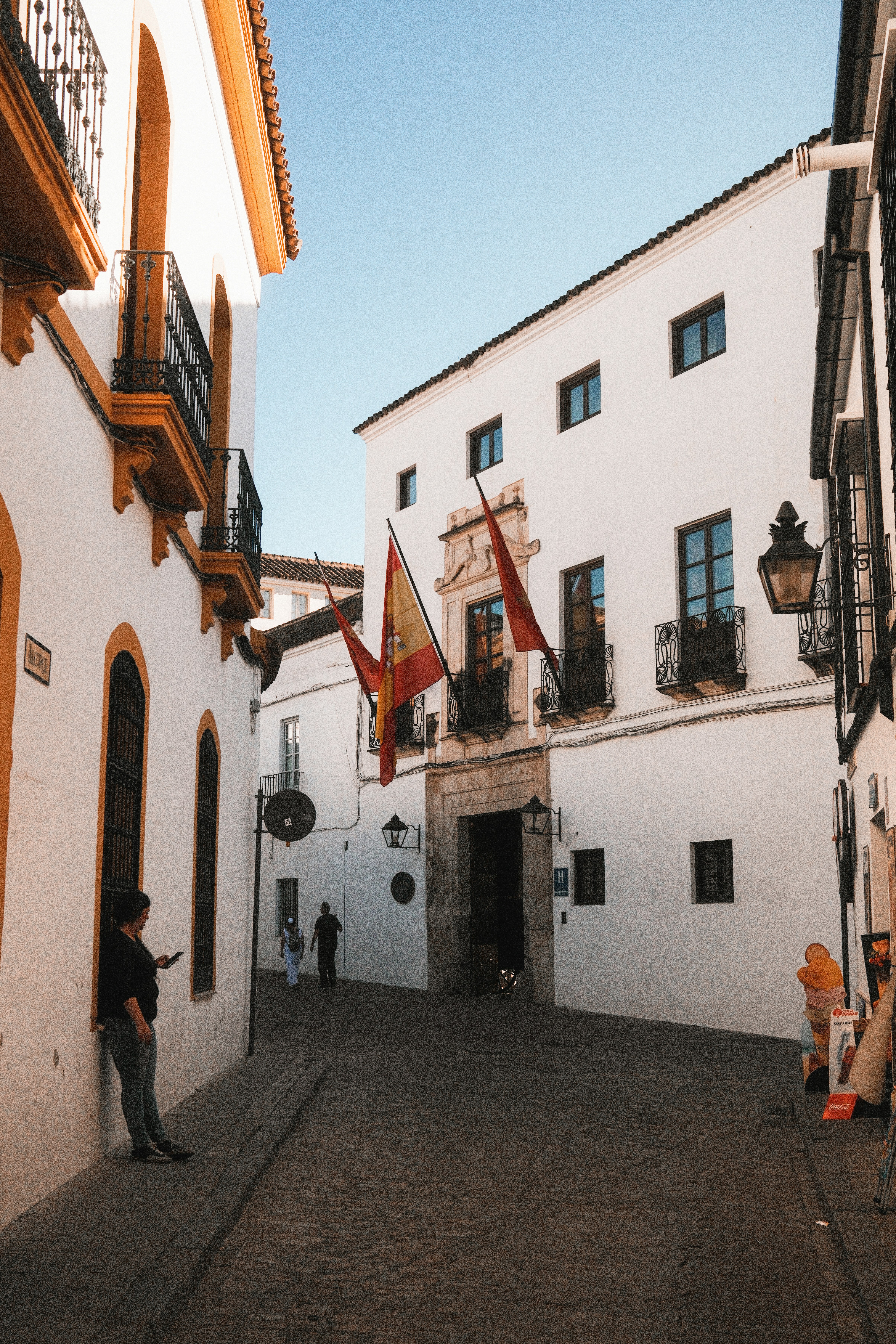 Sunlit Calle: Flags Framing a White-Washed Archway