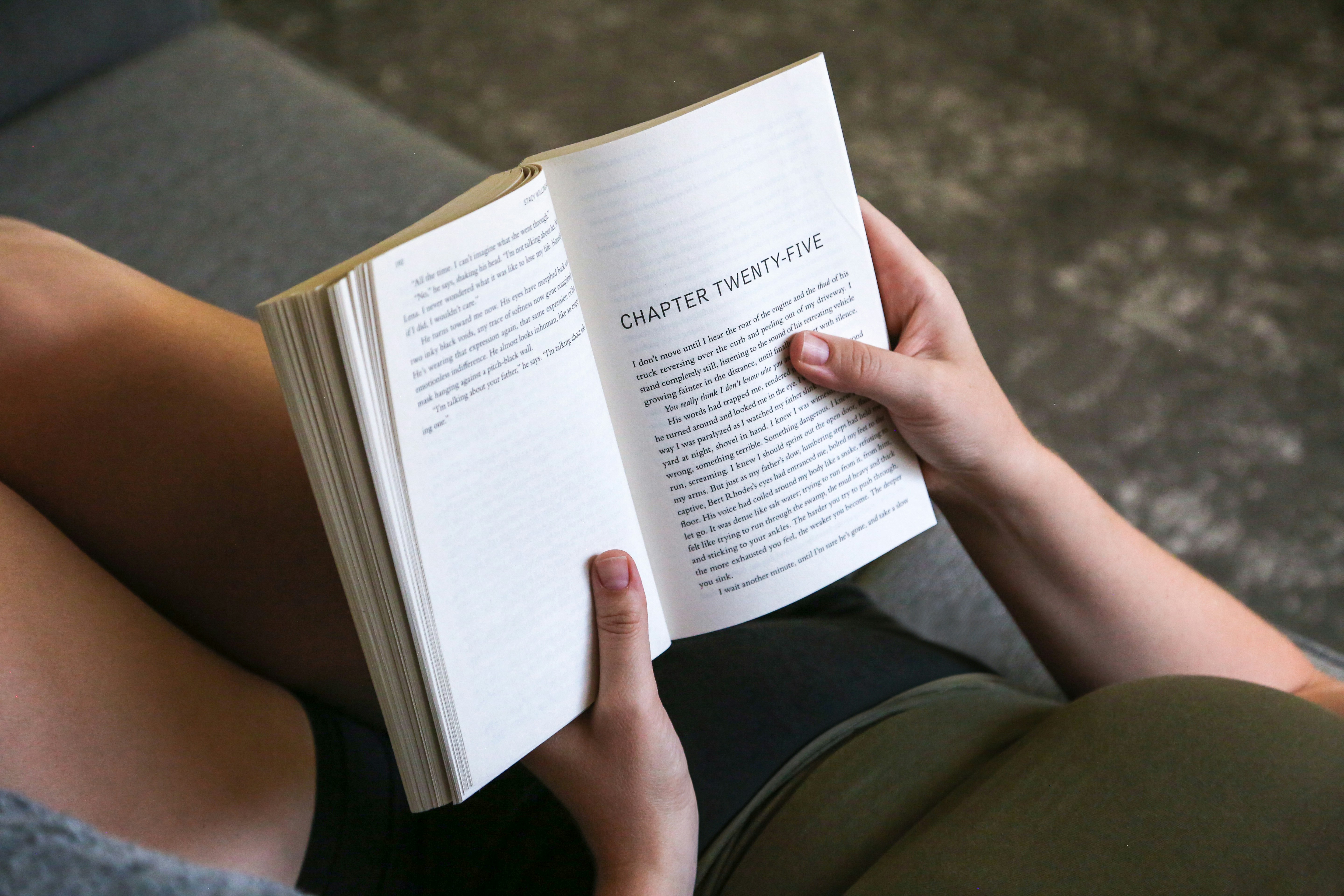A person sitting on a couch reading a book photo – Free School Image on ...