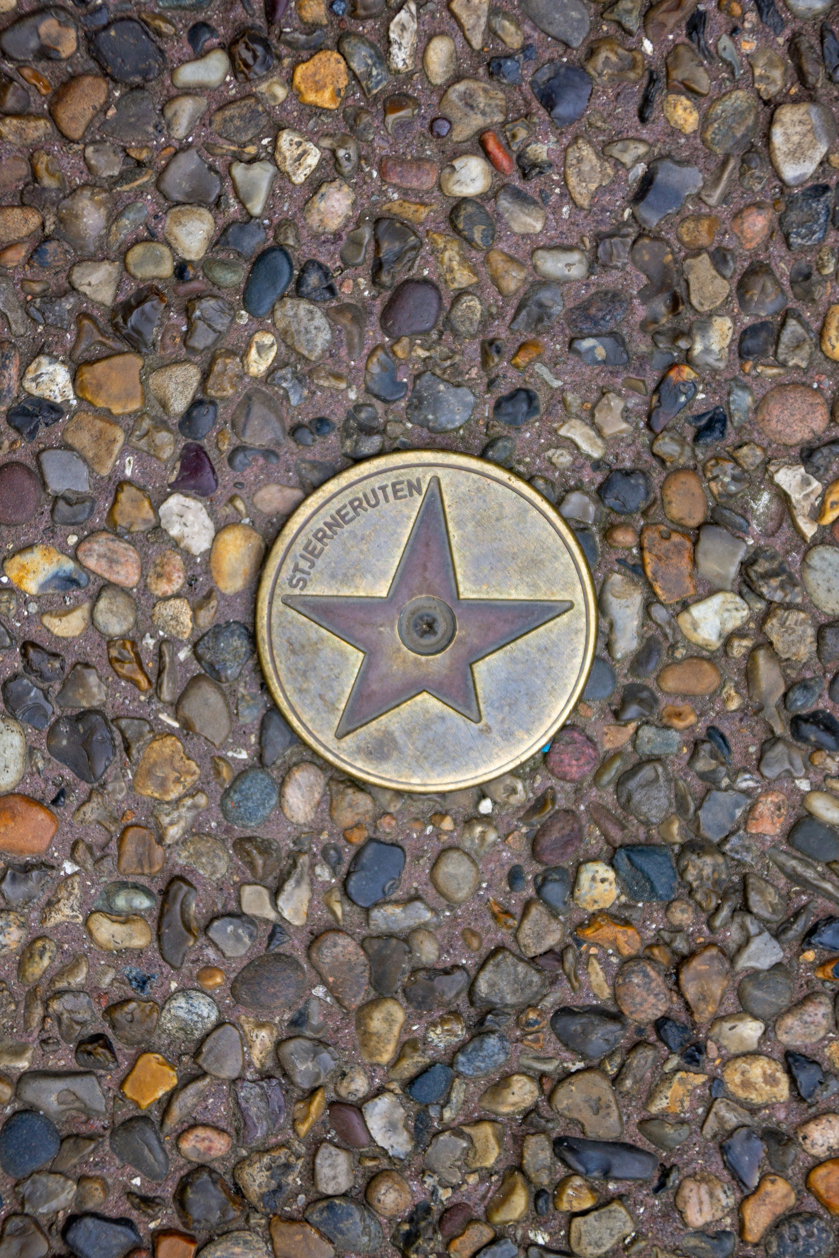 Pavement Star Marker Amidst Pebbles