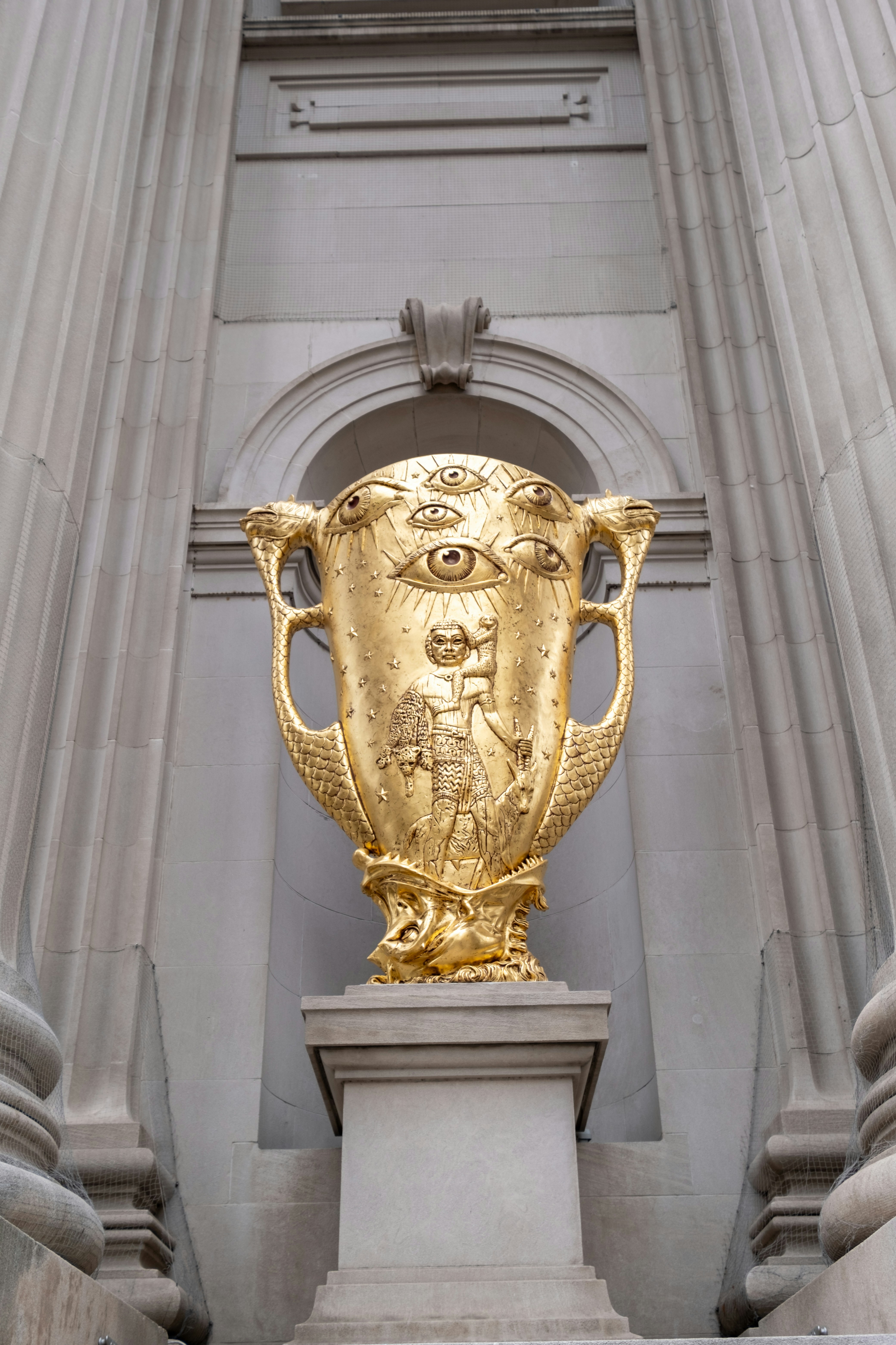 A large golden trophy sitting in front of a tall building photo – Free ...