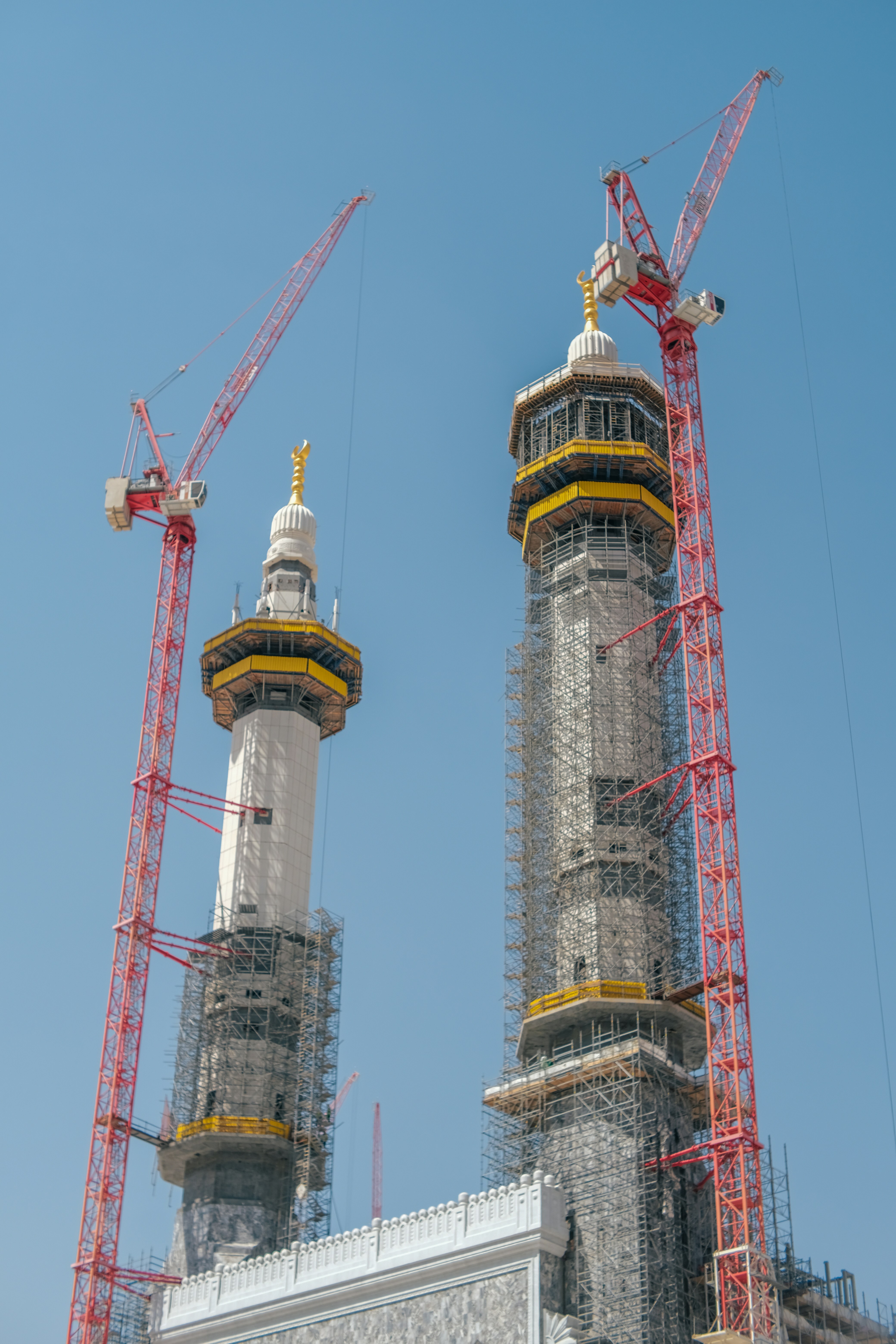 Skyward Progress: Twin Towers Wrapped in Scaffolds and Red Cranes