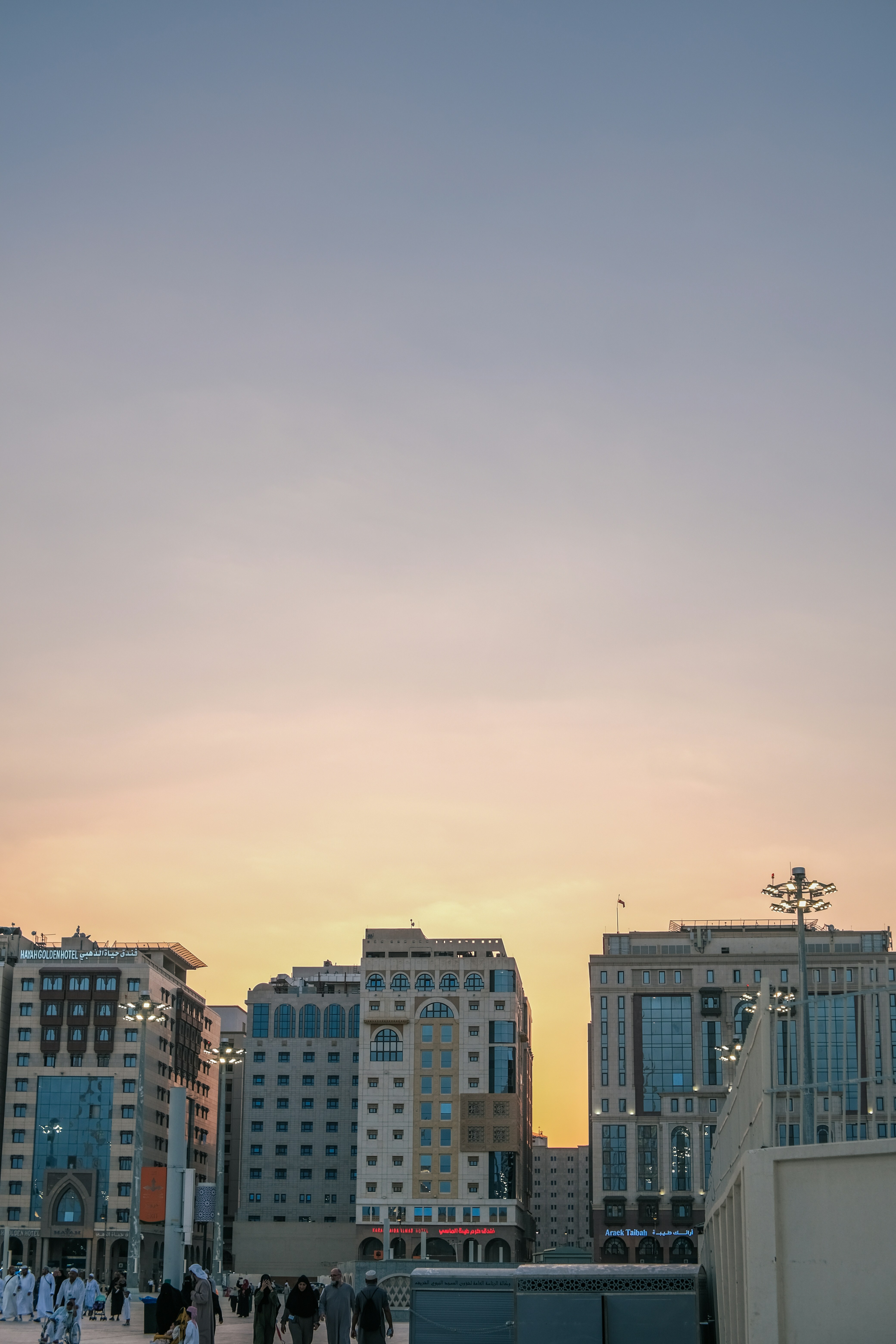 A group of people walking on a sidewalk in front of tall buildings ...
