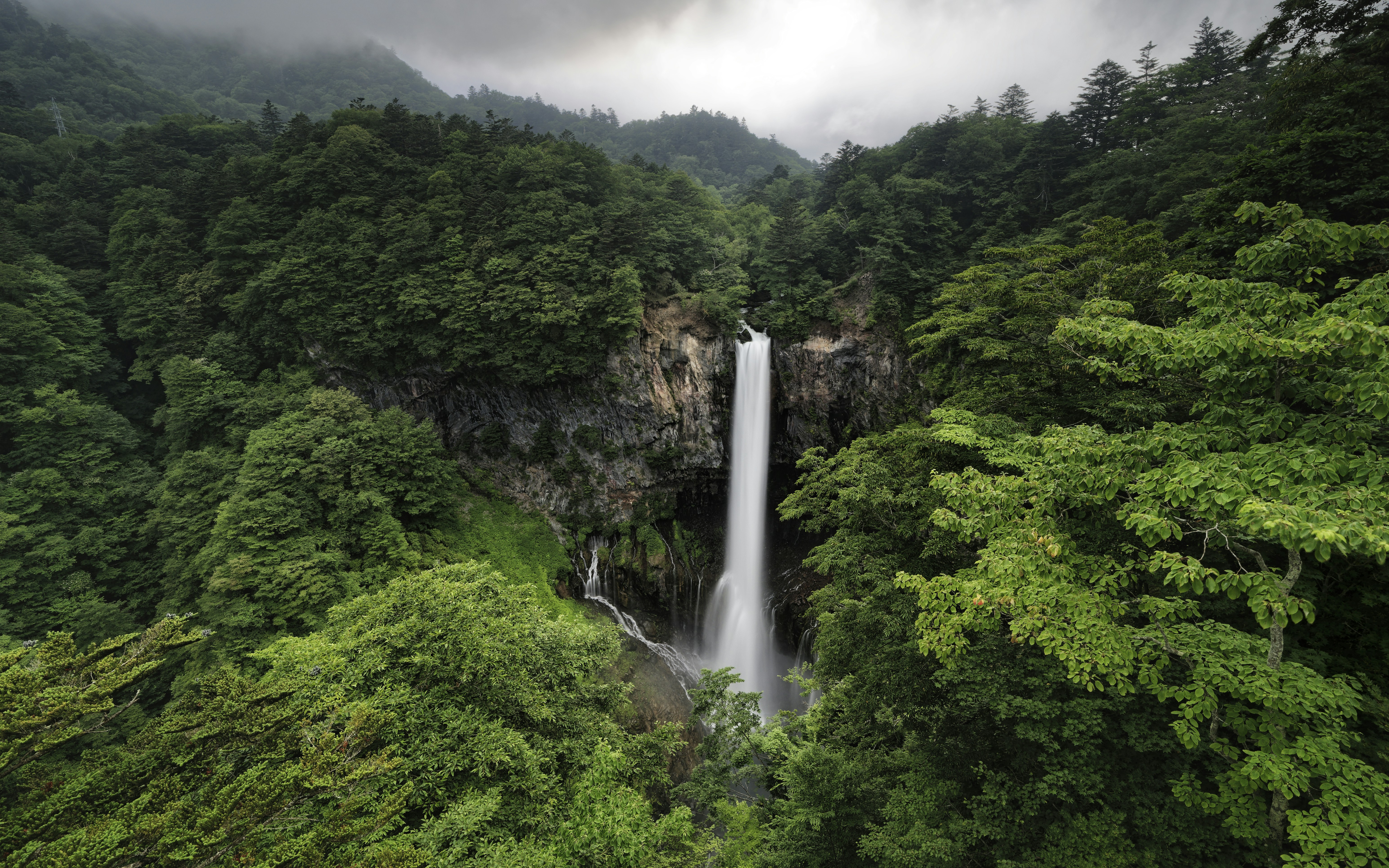 A large waterfall surrounded by lush green trees photo – Free Nature ...