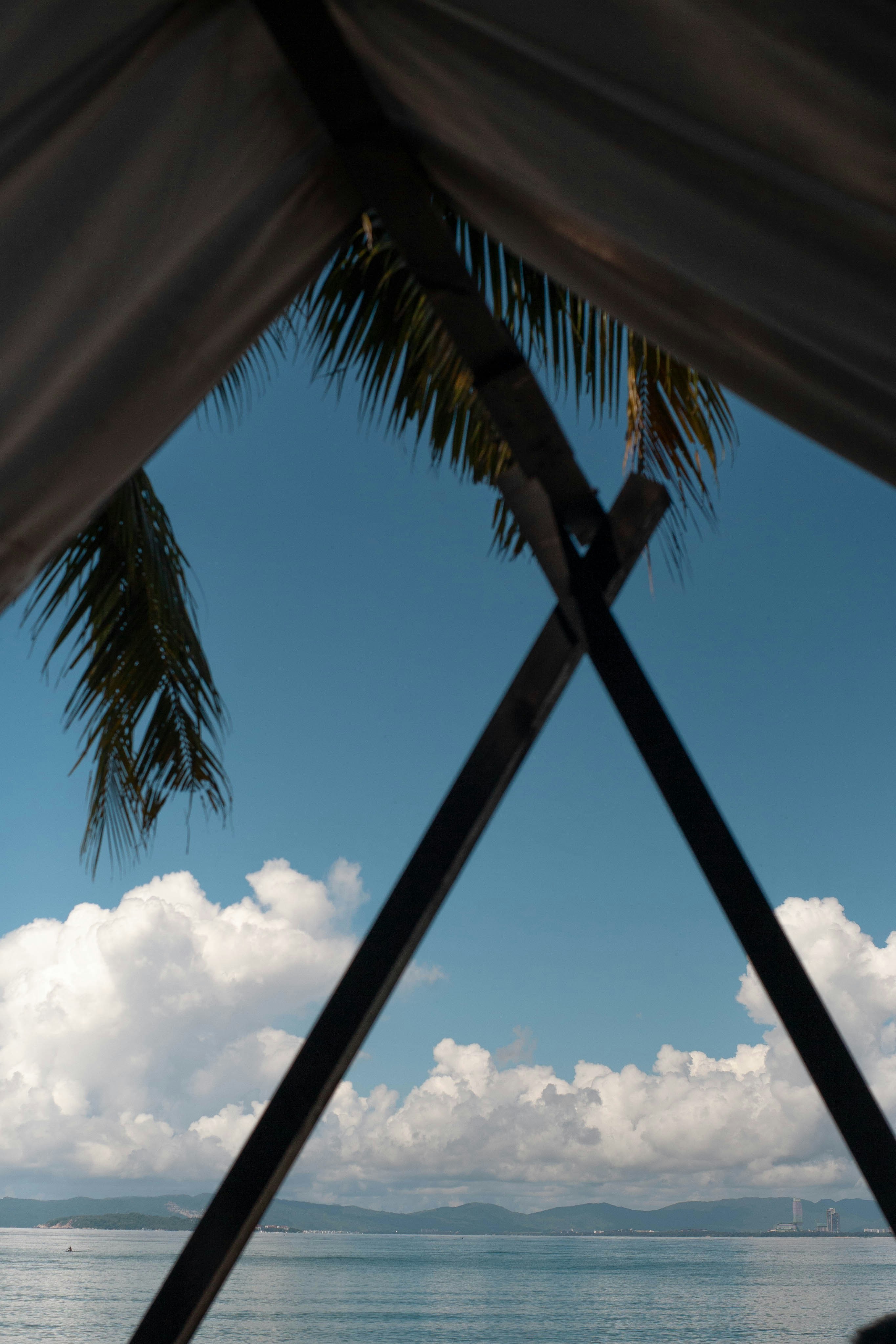 X-shaped palm-framed horizon under a fabric canopy