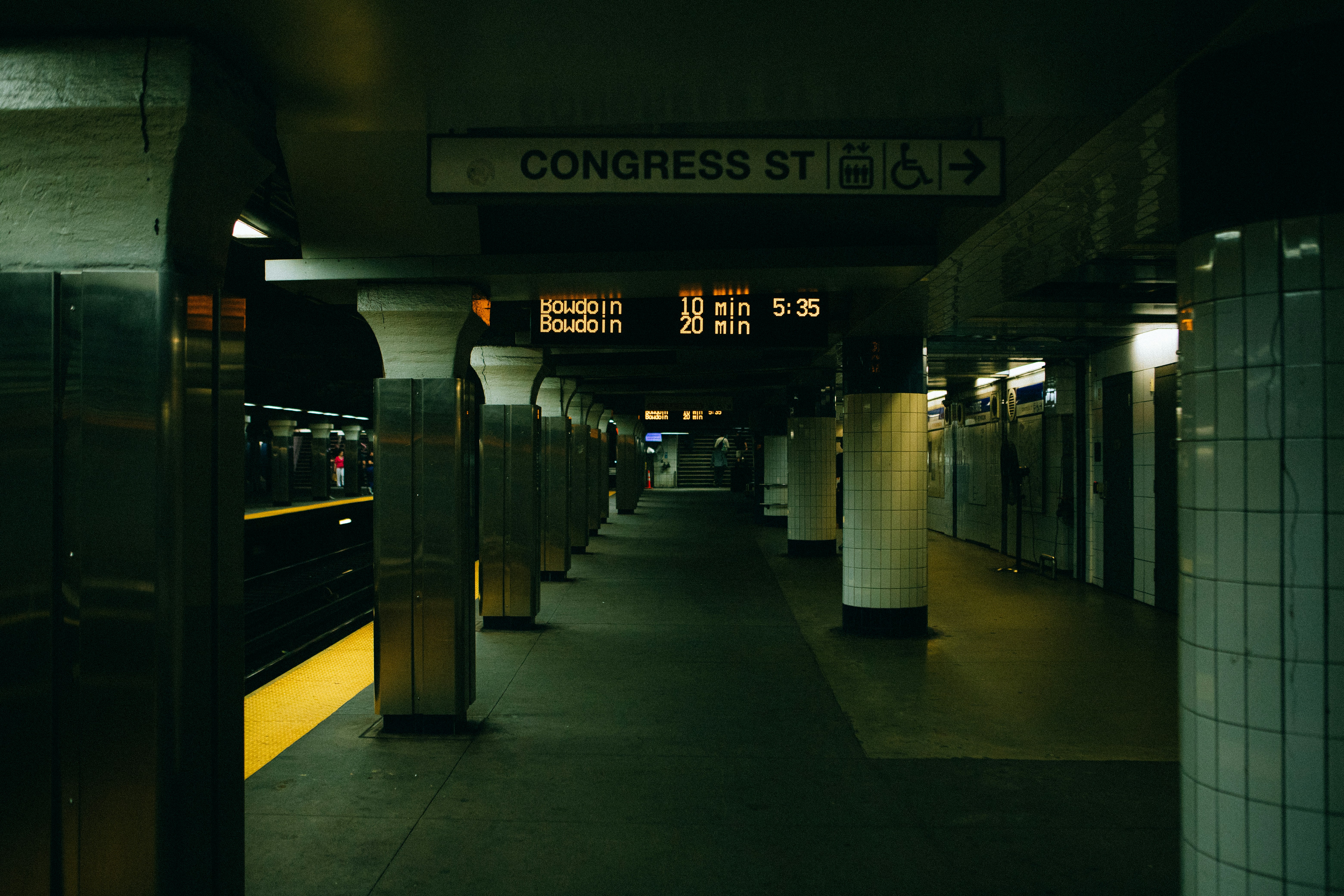 A dimly lit subway station with people waiting photo – Free Boston ...