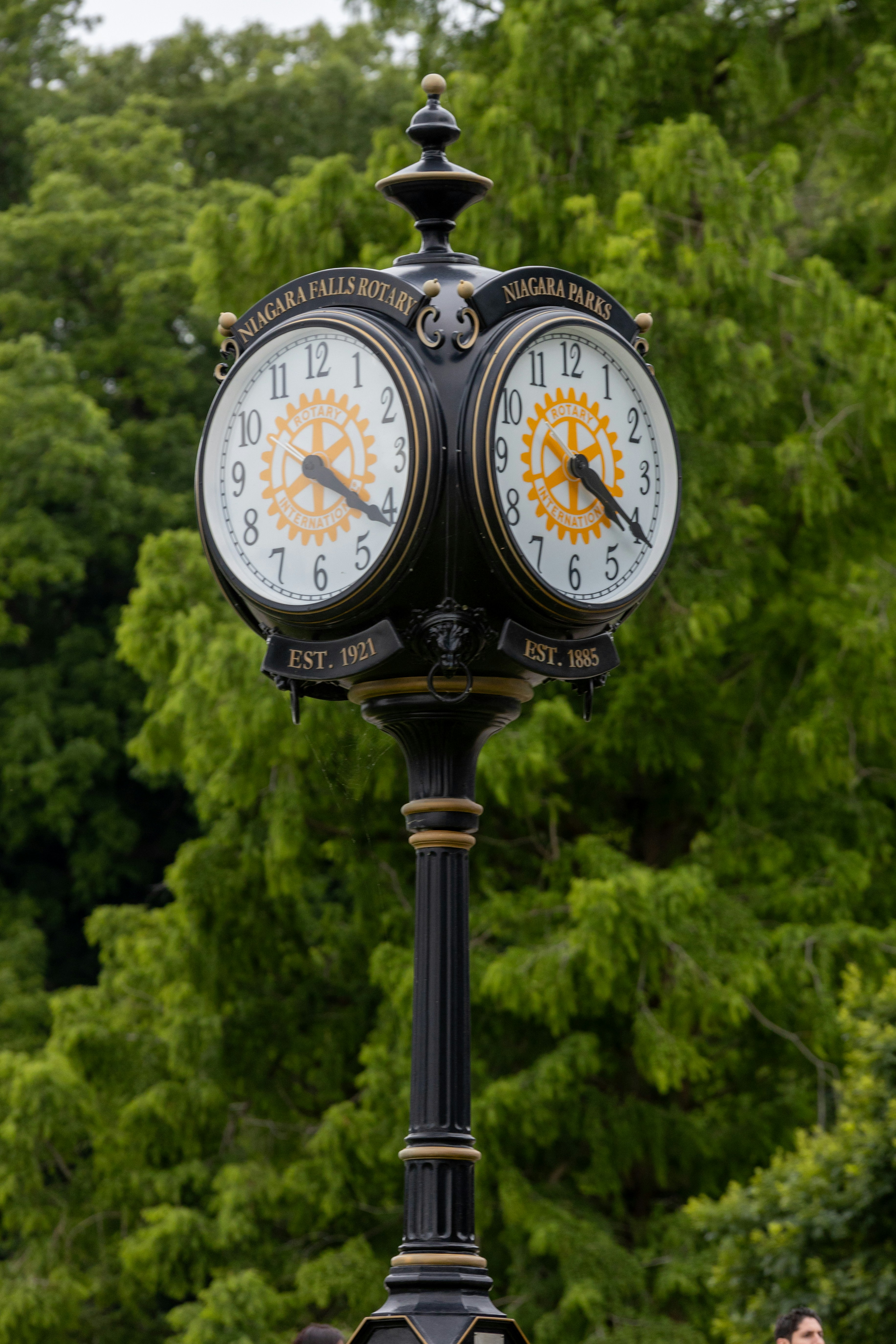 A retro clock tower in front of a leafy background