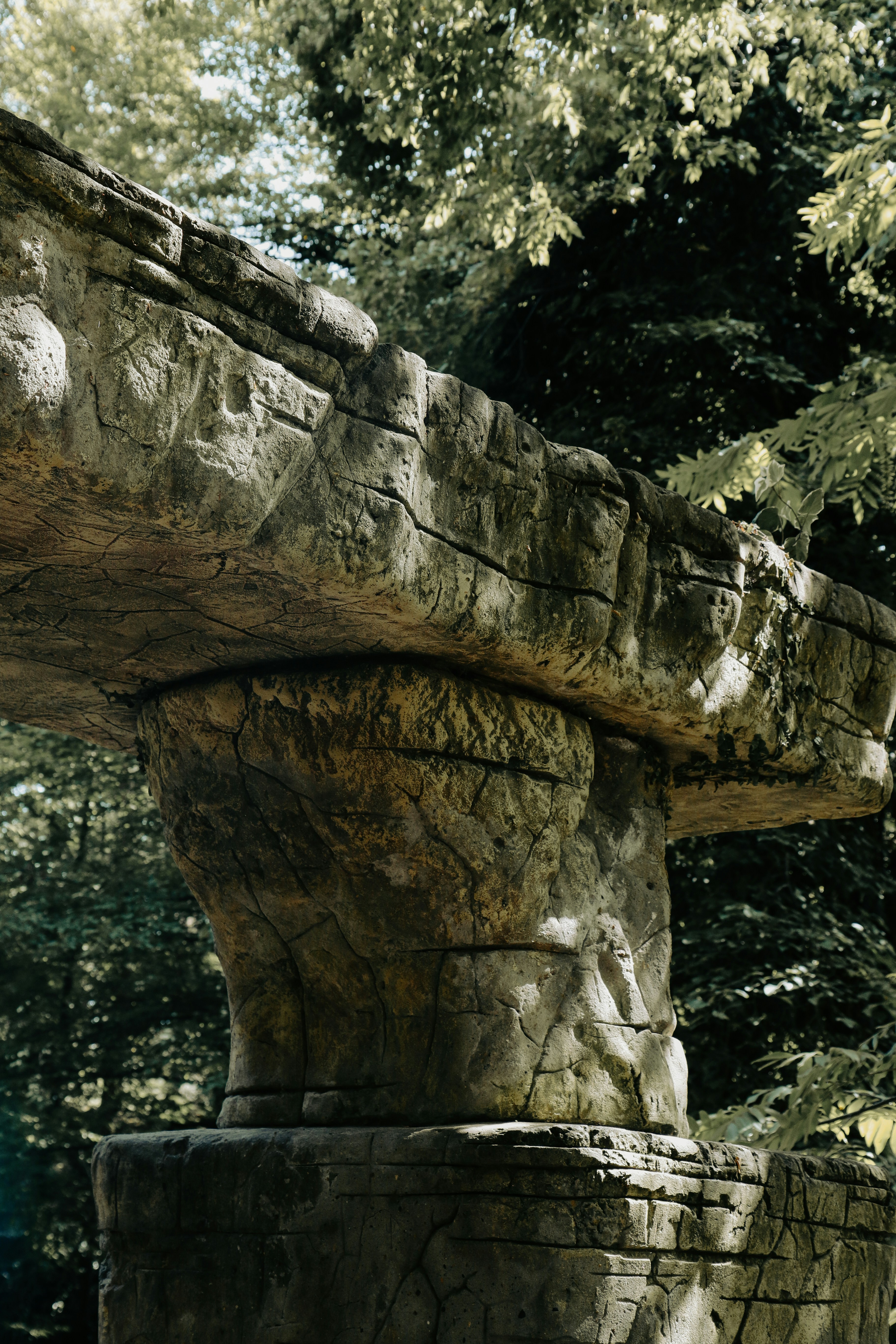 Keystone in the Green Cathedral: Weathered Bridge Pillar Under a Forest Span